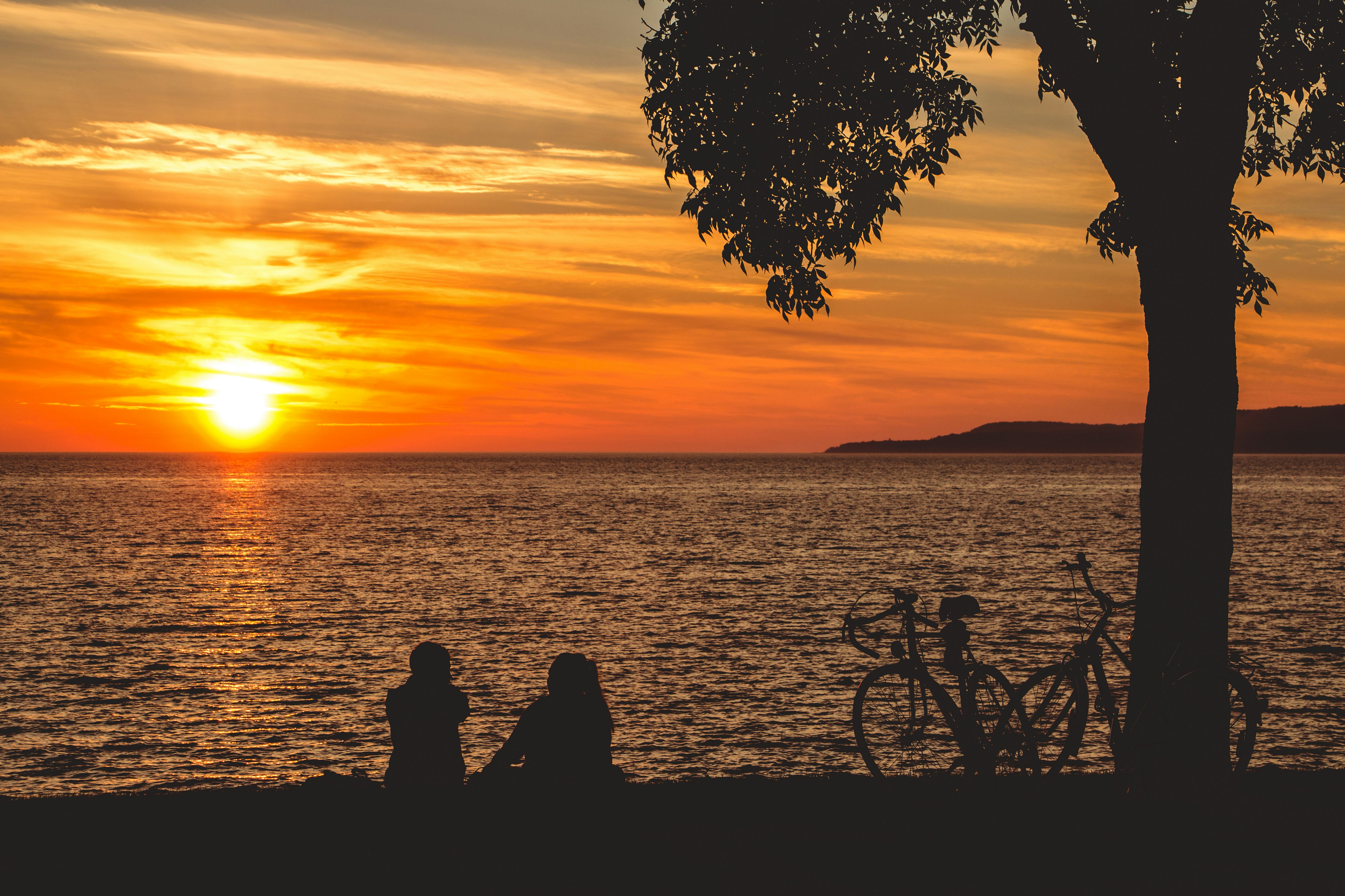 Dusk by the Shore: Silhouettes, a Bicycle, and a Golden Horizon