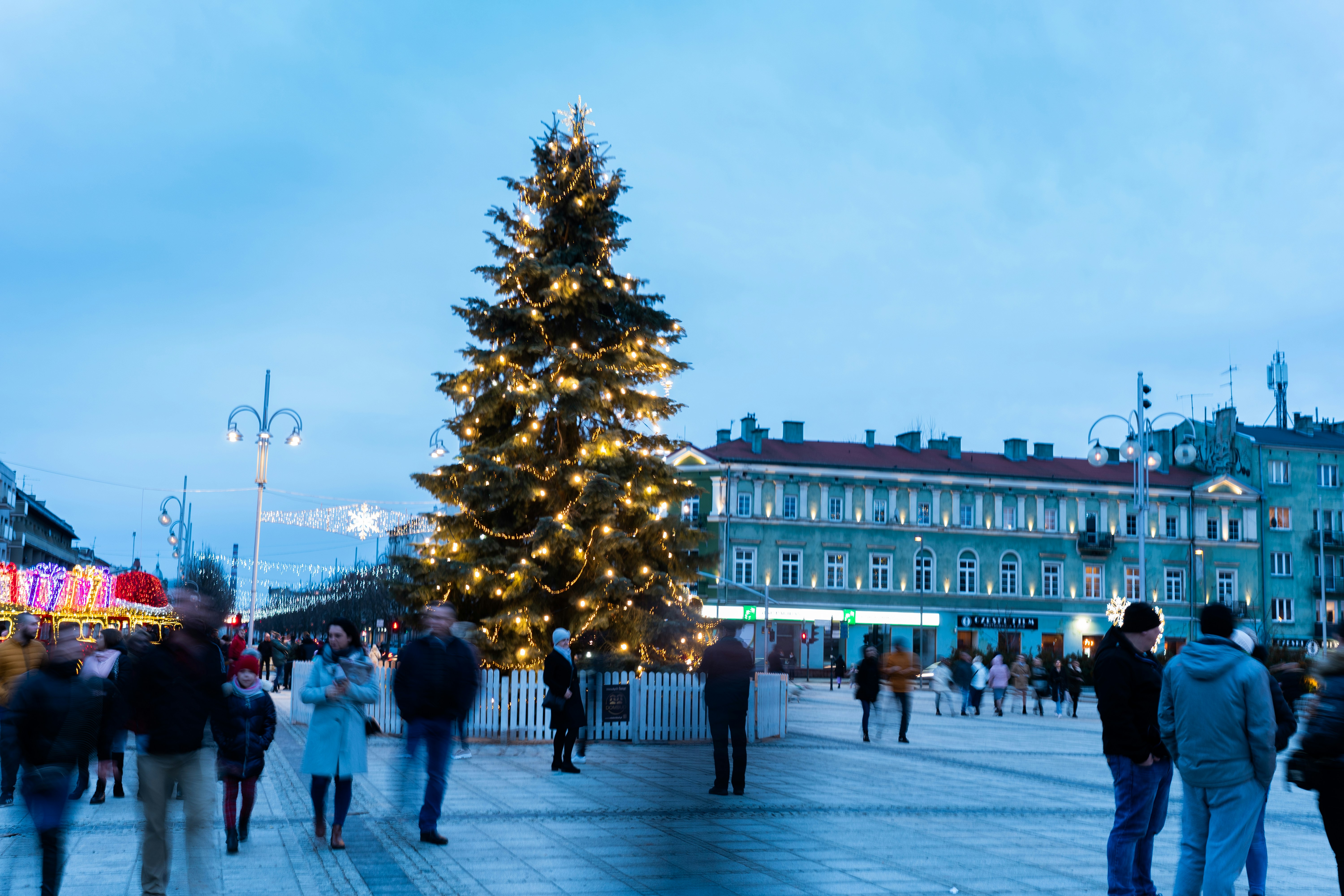 A group of people standing around a christmas tree photo – Free ...