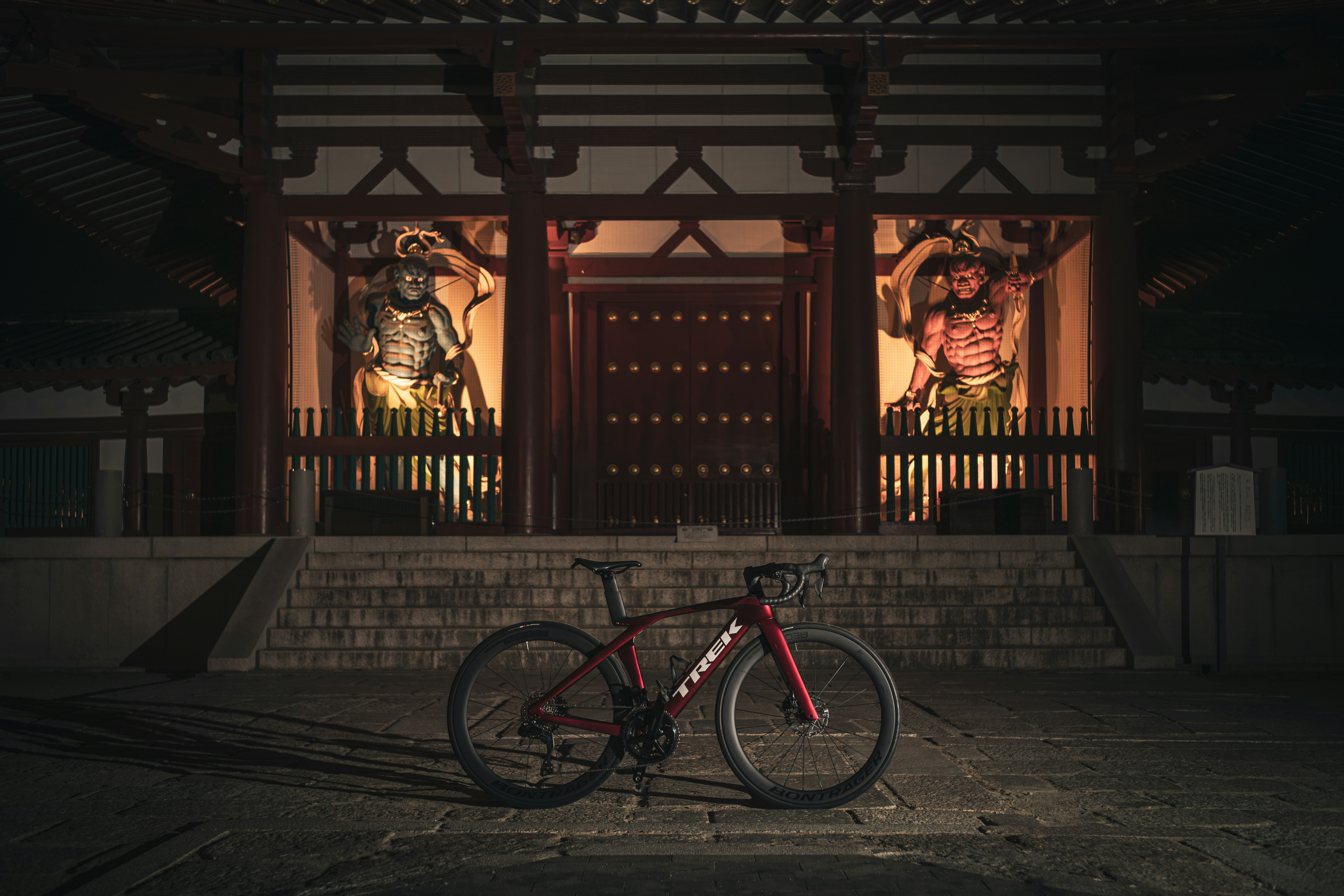 Crimson Bicycle at the Temple Gate, Nightlit Guardians Watching