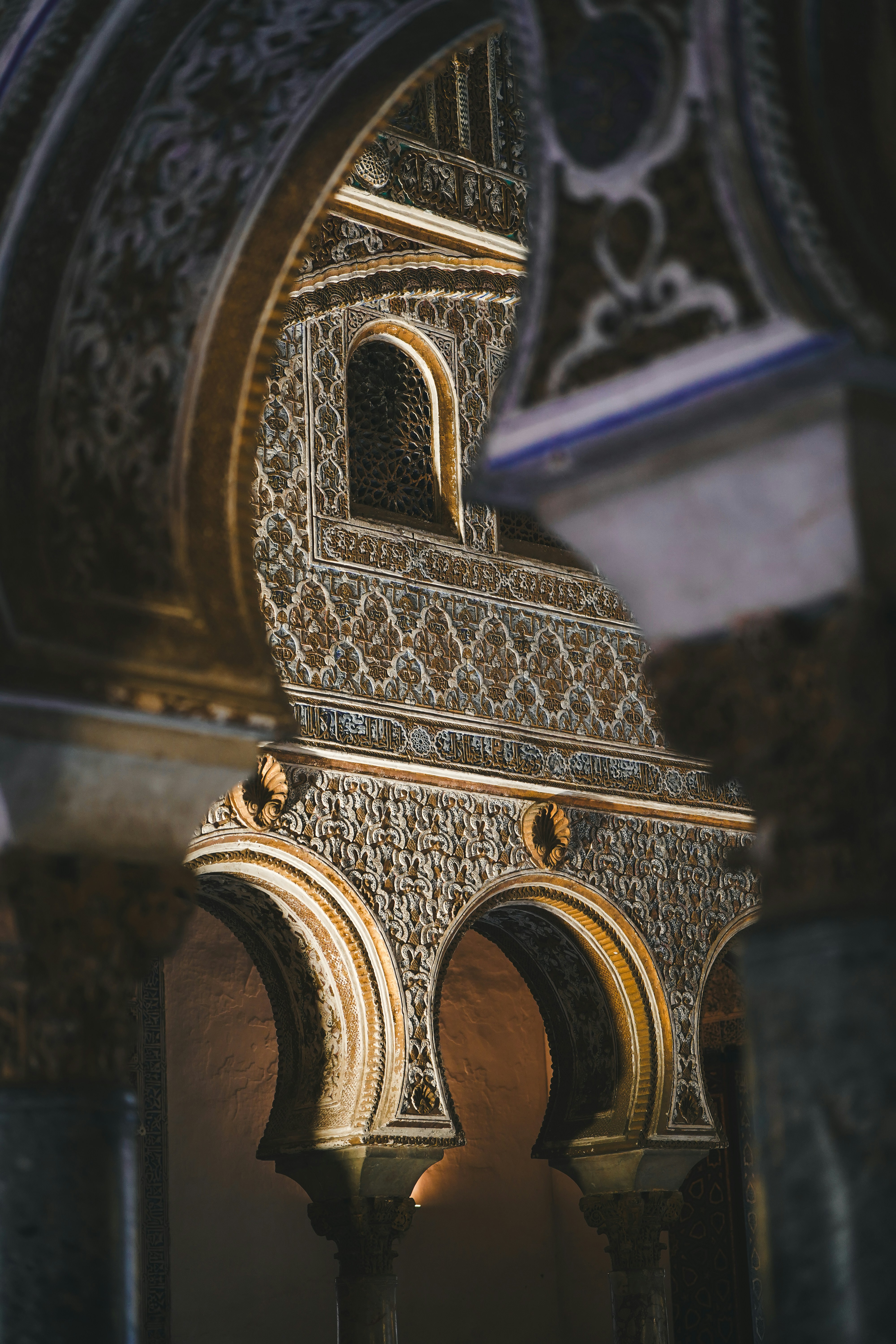 Ornate archways and intricate floral tilework in a historic arcade, illuminated by warm directional light.