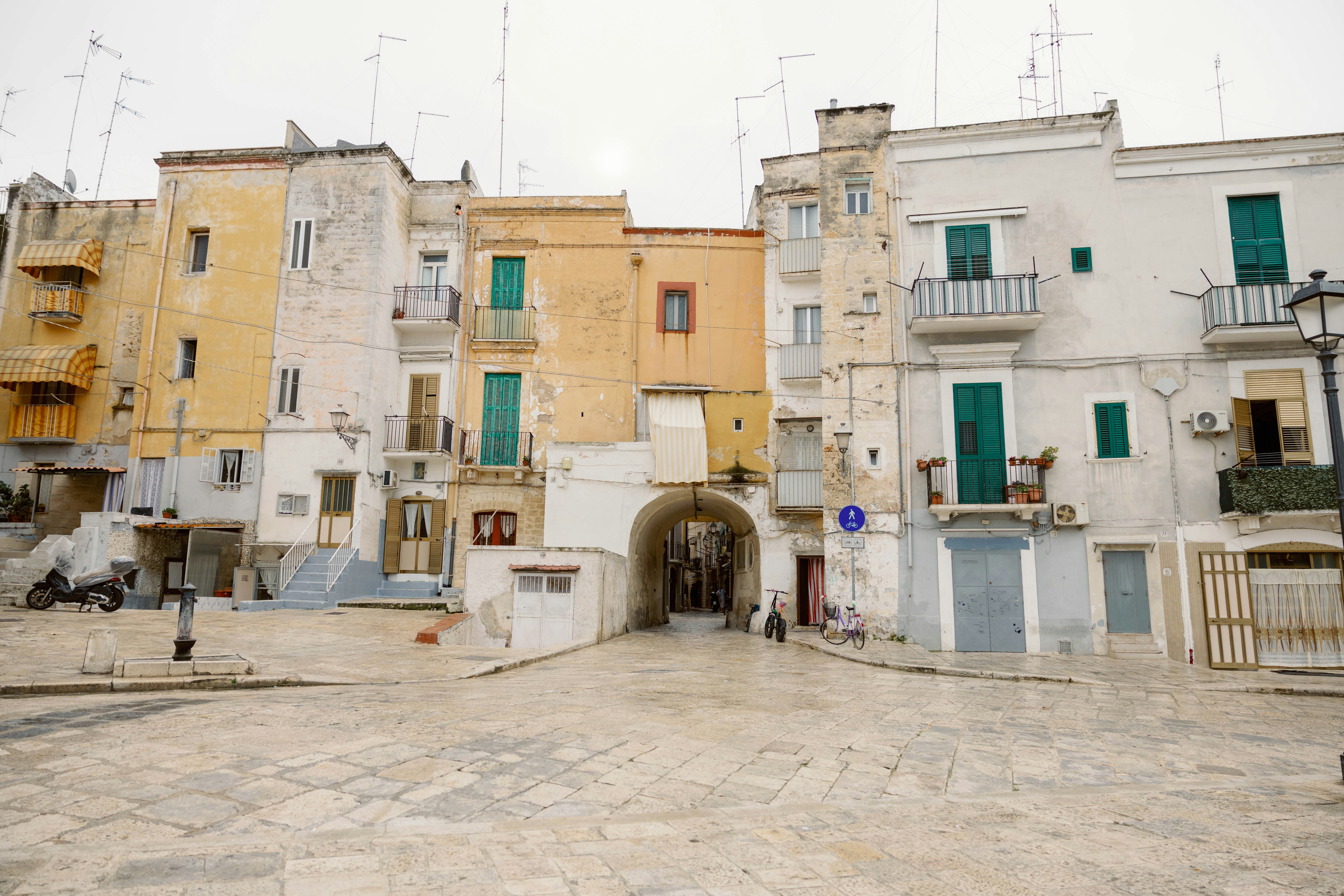 Colorful, aged buildings line a quaint, sunlit plaza with weathered textures.