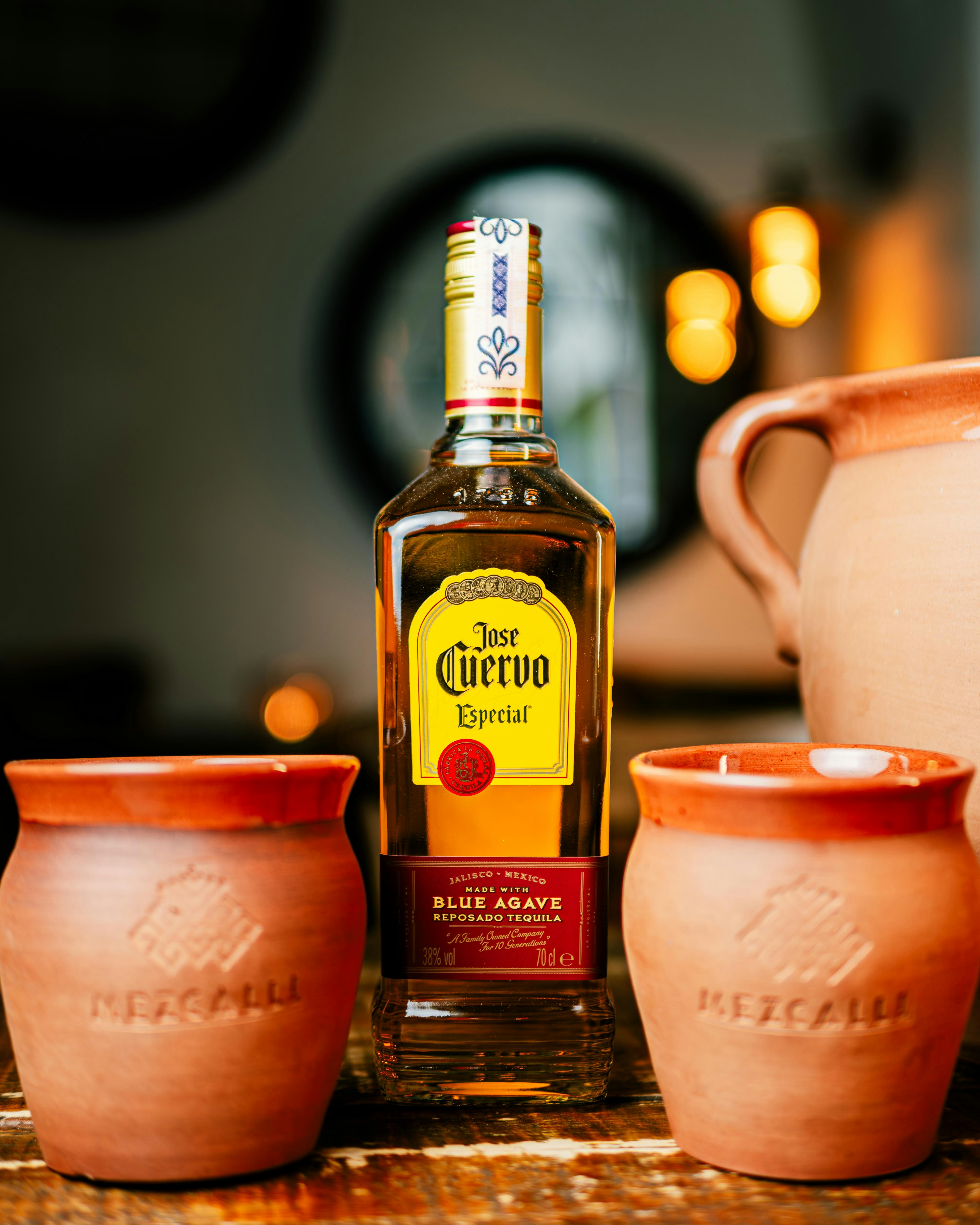 a bottle of alcohol sitting next to three cups