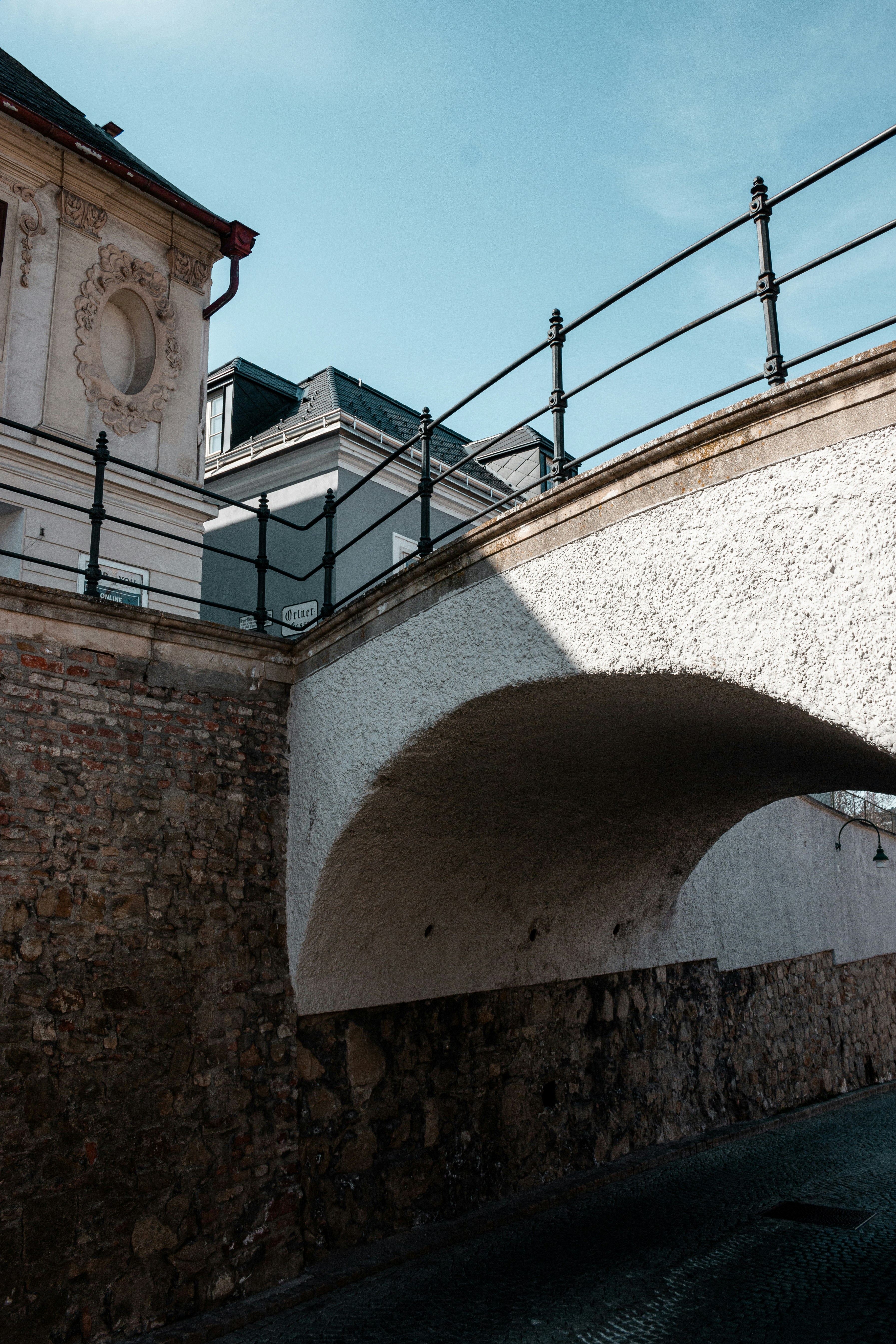 Arc of Light: Sunlit Bridge Arch Over a Weathered Cobblestone Passage