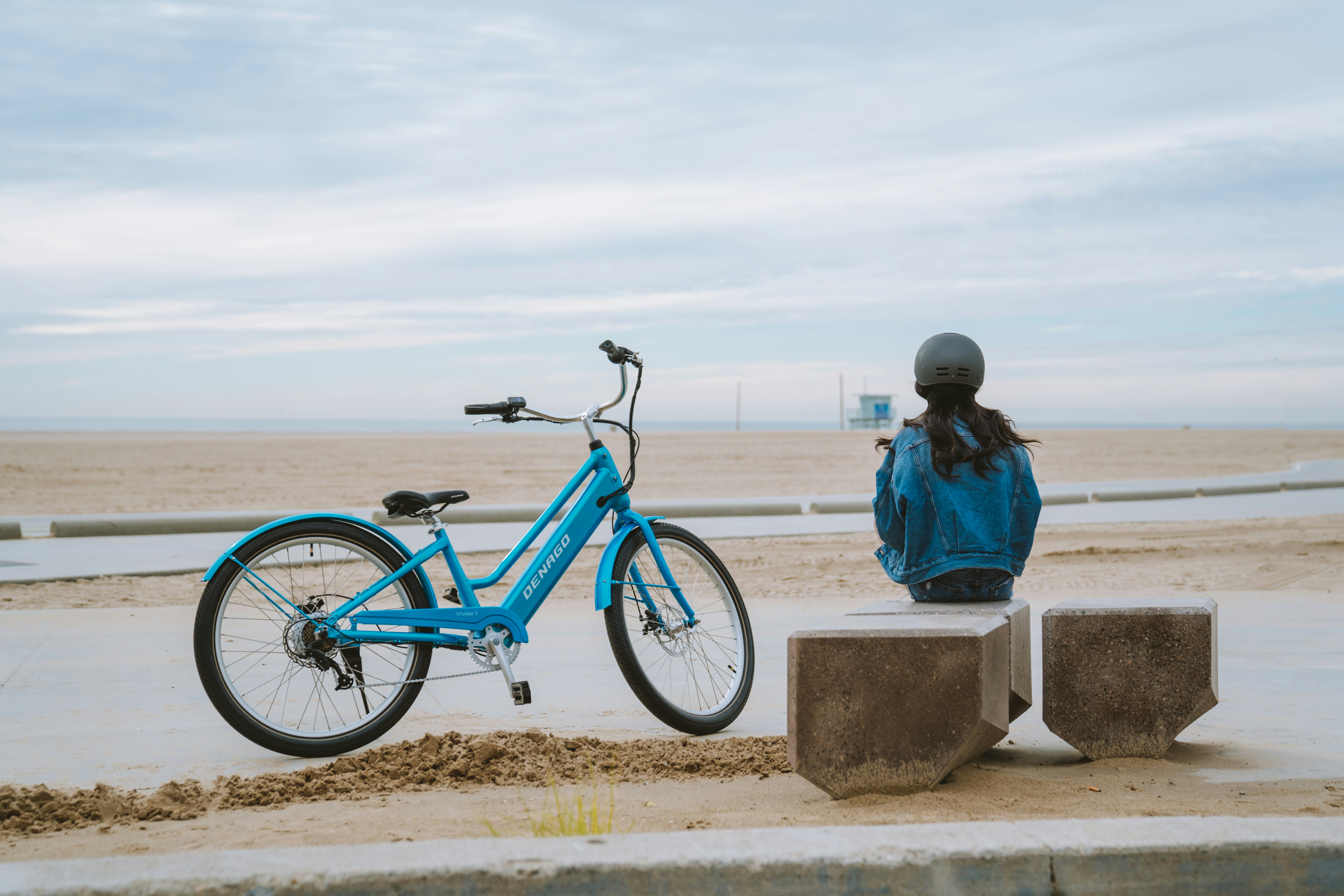 Blue bicycle and contemplative rider by a seaside promenade