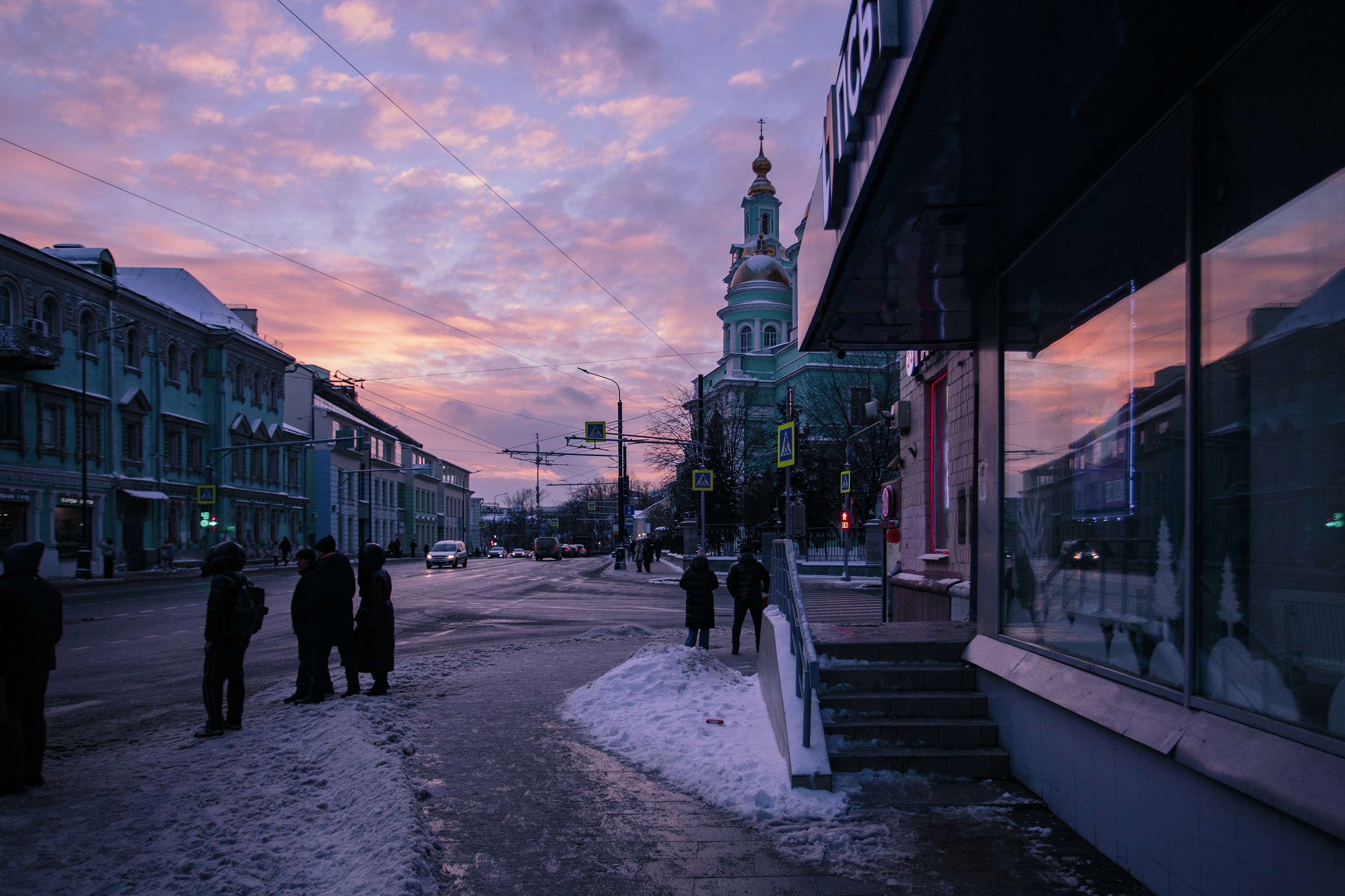 Dusk Over Snow-Blanketed Street Toward a Green-Domed Church Tower