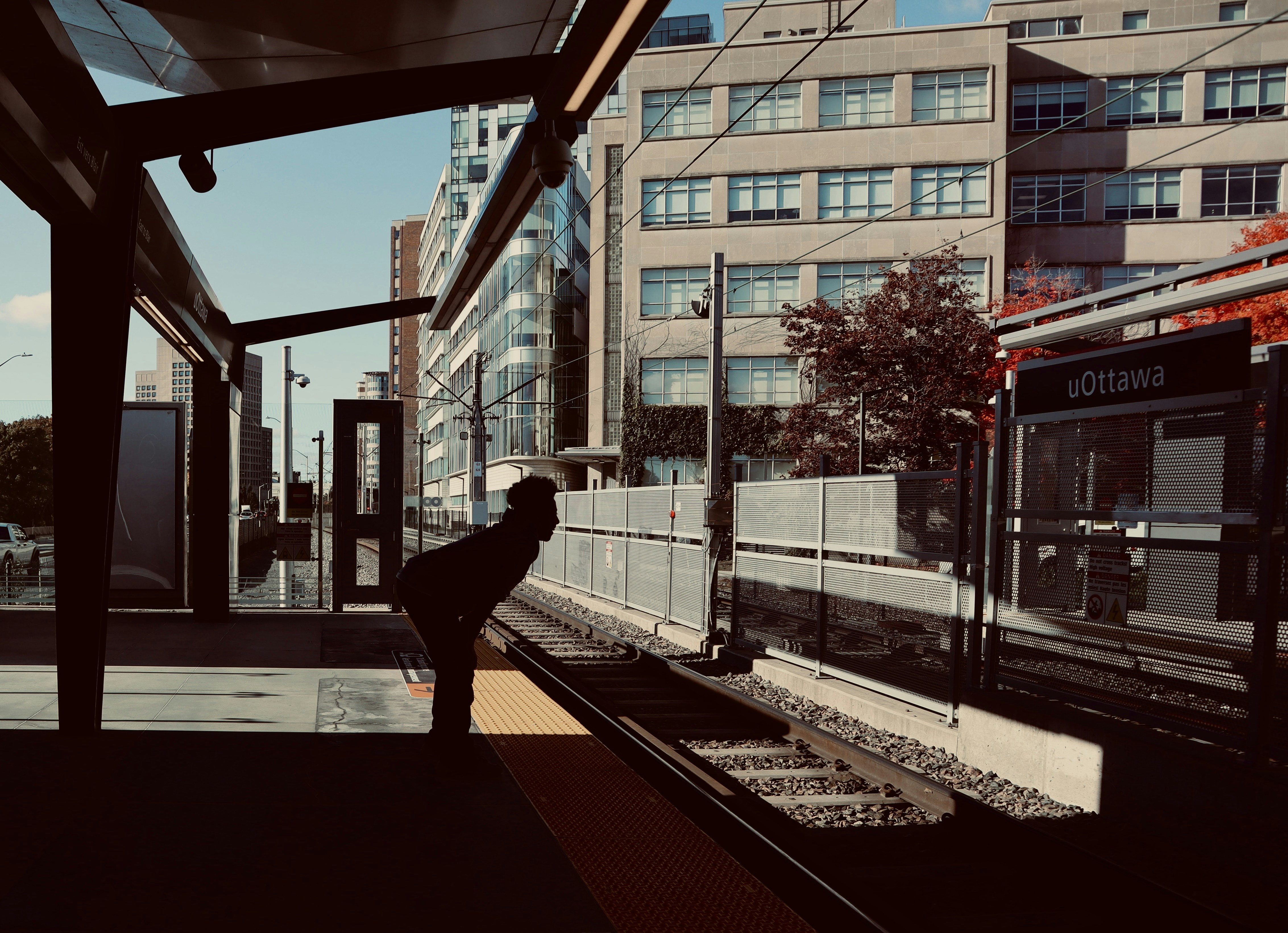 Lone Silhouette at the Platform's Edge Beneath Urban Glass