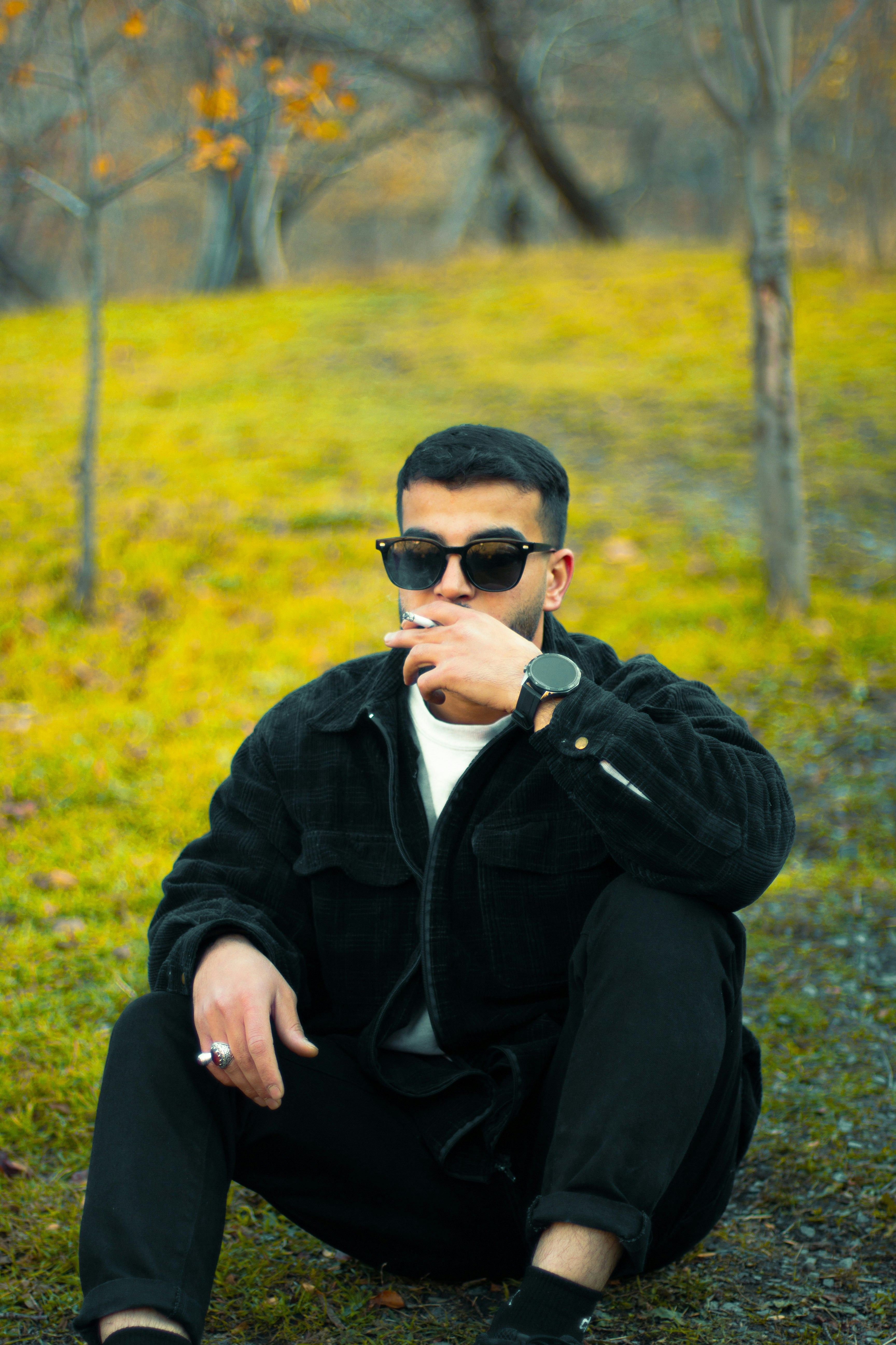 A man sitting on the ground smoking a cigarette photo – Free Face Image ...