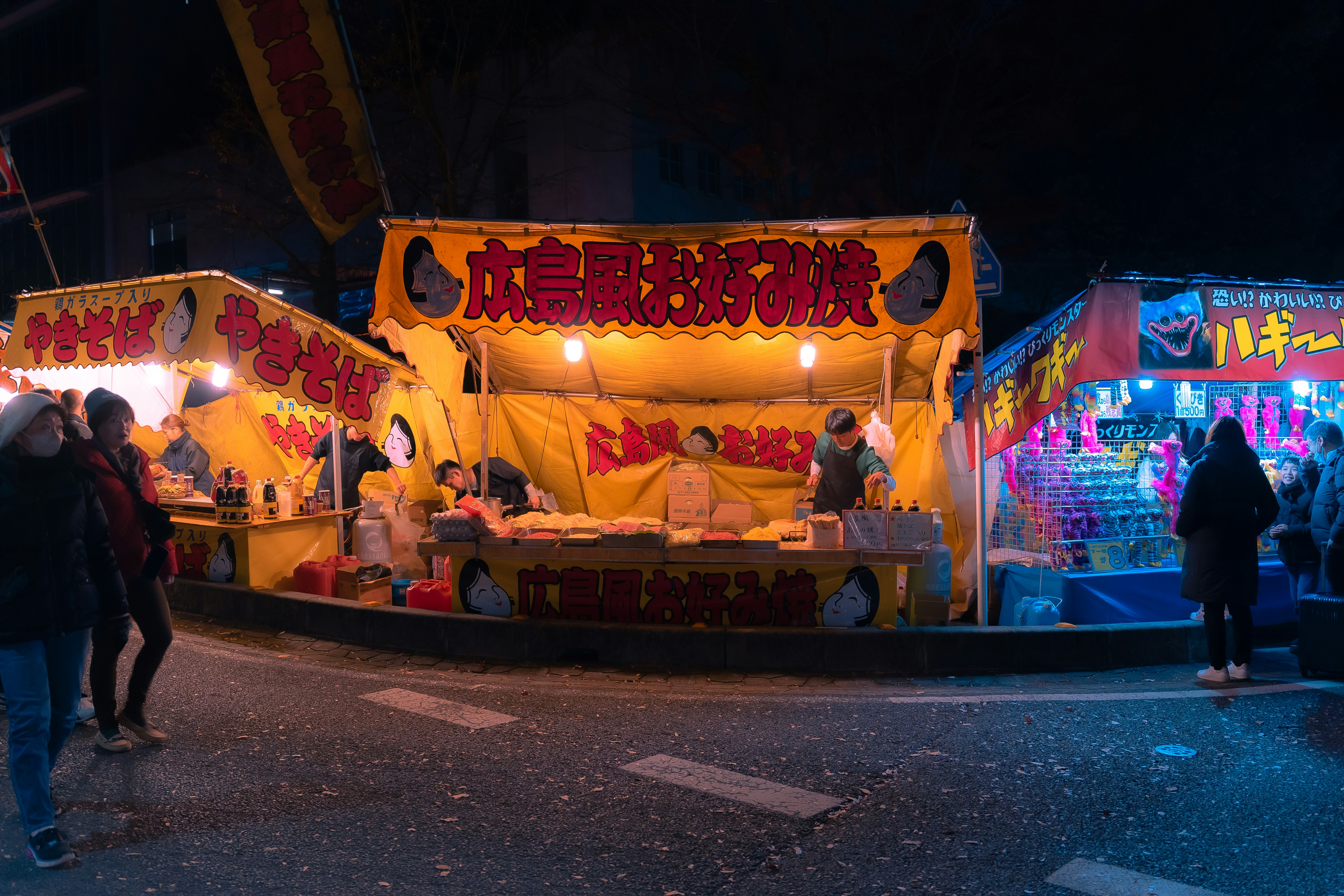 Vibrant food stalls illuminated at a bustling night market.