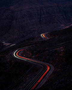 Serpentine Night Drive: Light Trails Winding Through a Shadowed Canyon