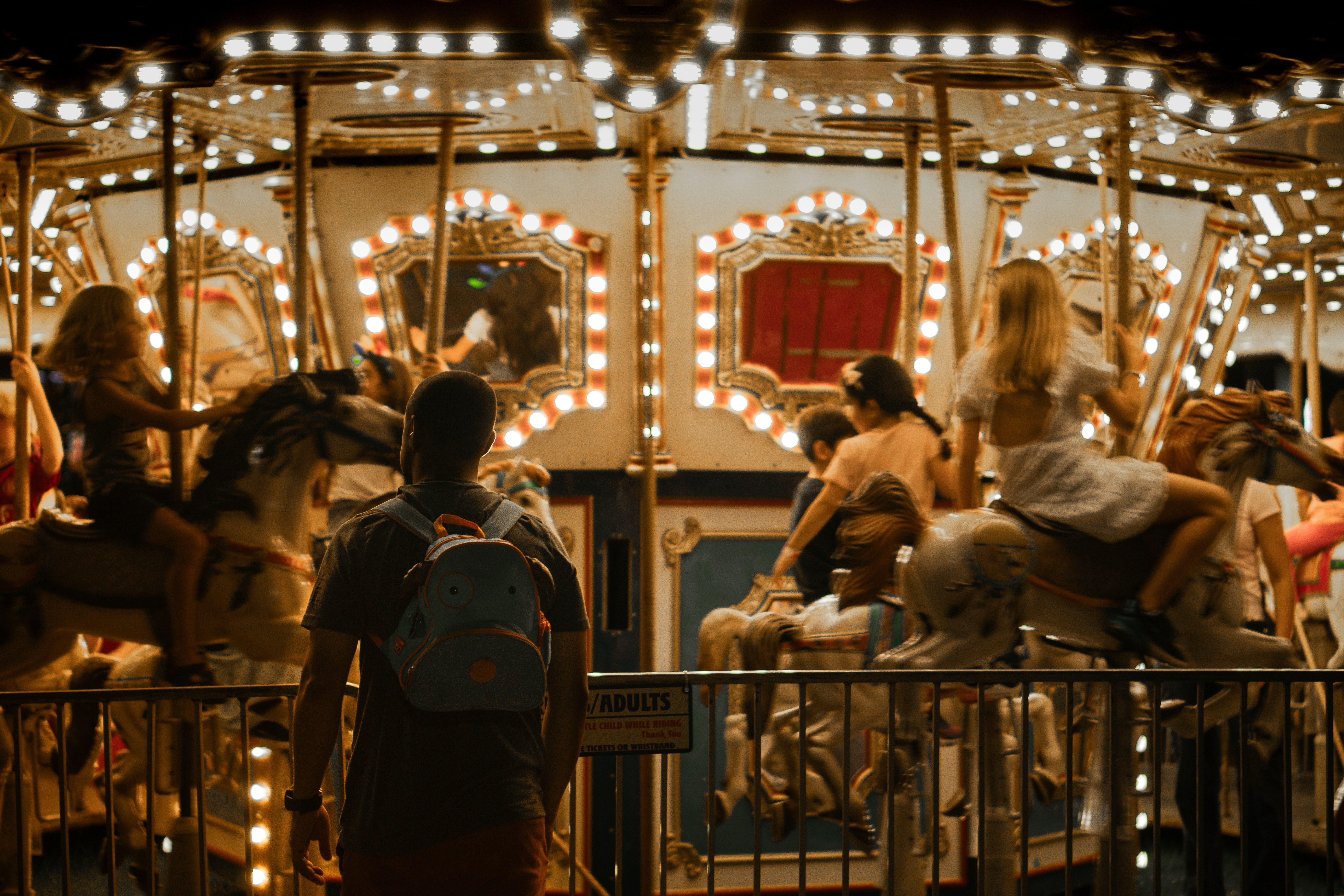 Backpack in the Carousel Glow: Night Ride Amid Golden Orbs