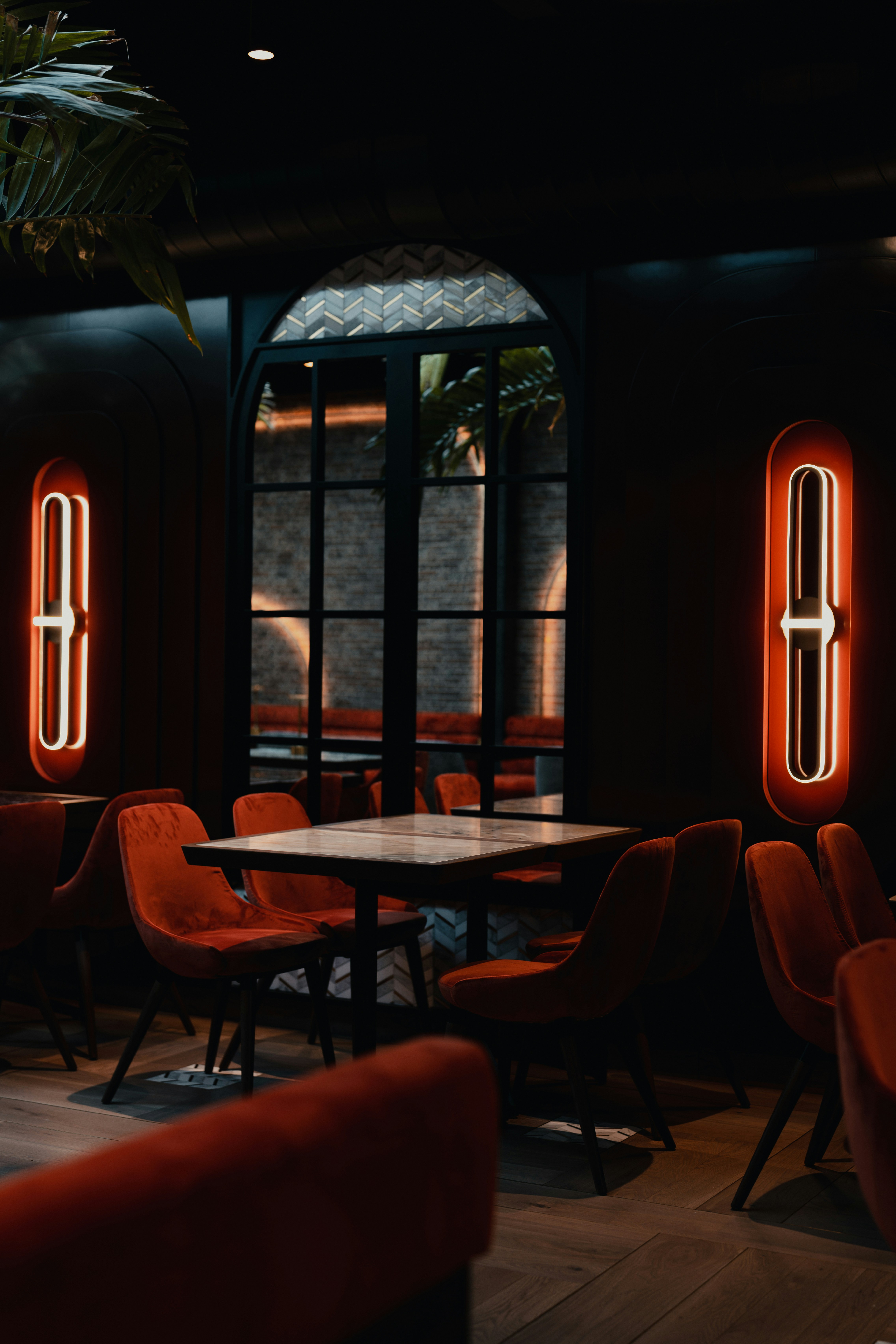 A dimly lit restaurant with orange chairs and a round table photo ...