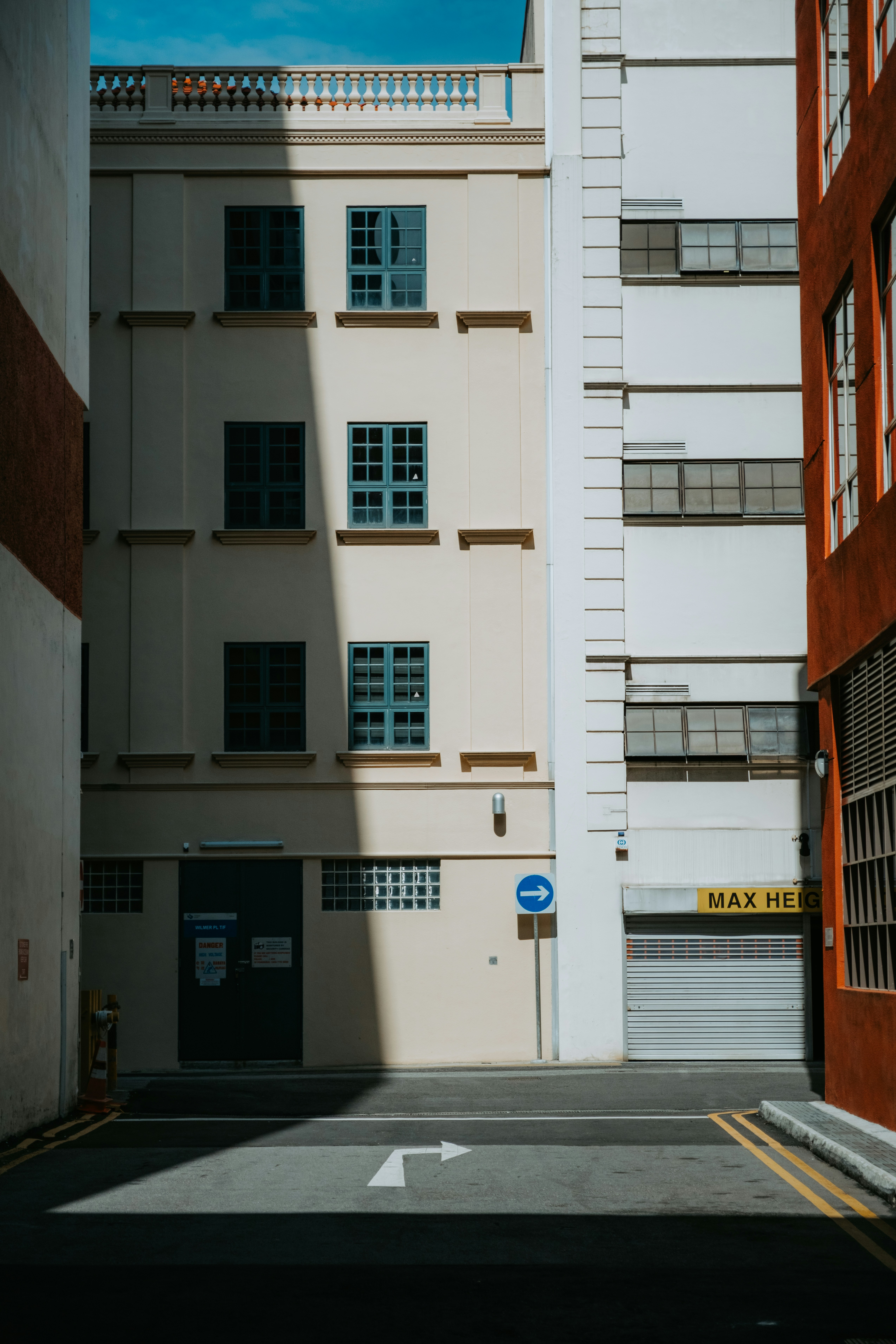 A narrow urban alleyway framed by contrasting buildings, showcasing a play of light and shadow. The scene captures architectural lines and textures.