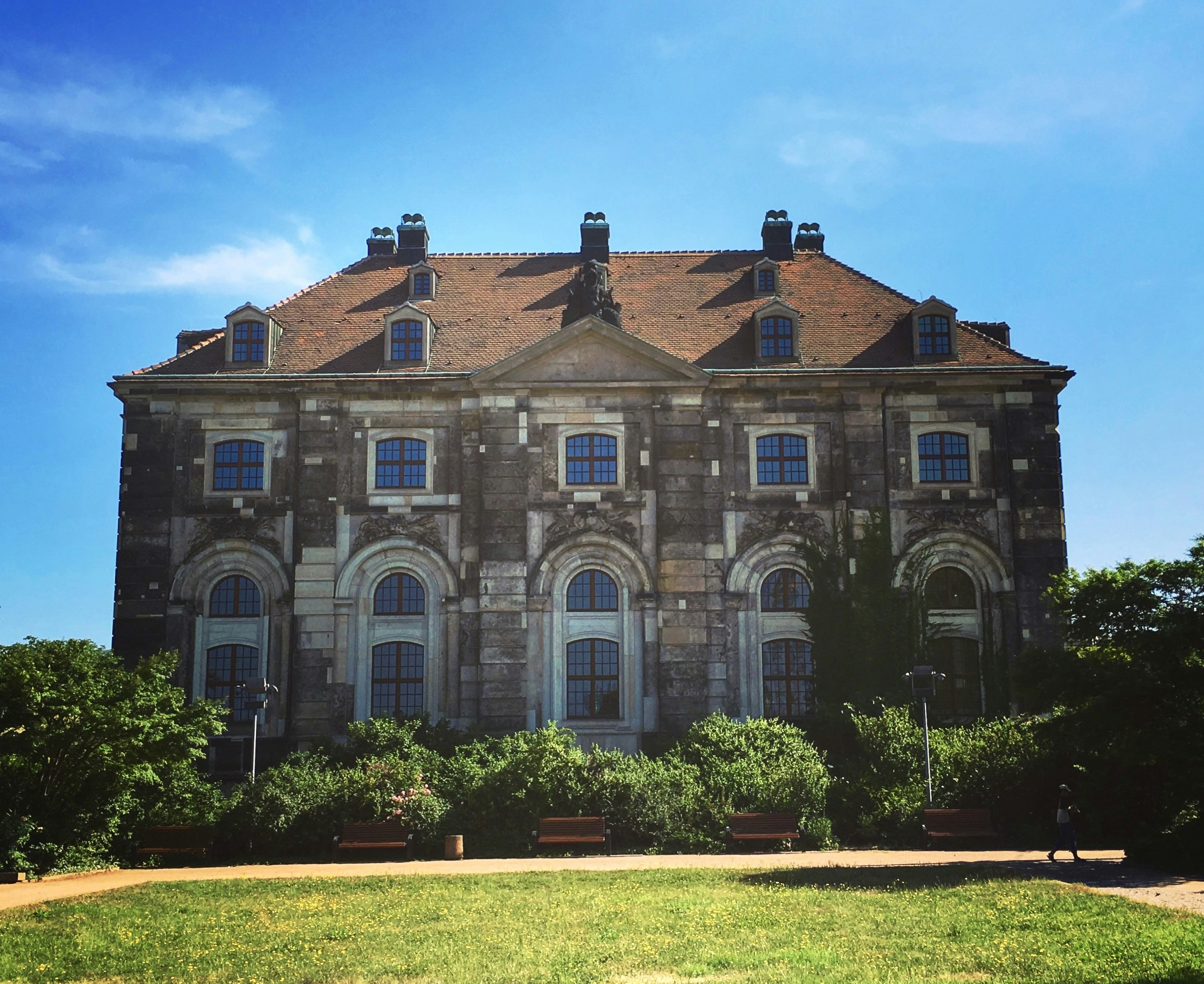 Centerline of Stone: The Neoclassical Manor Rising Under a Clear Blue Sky
