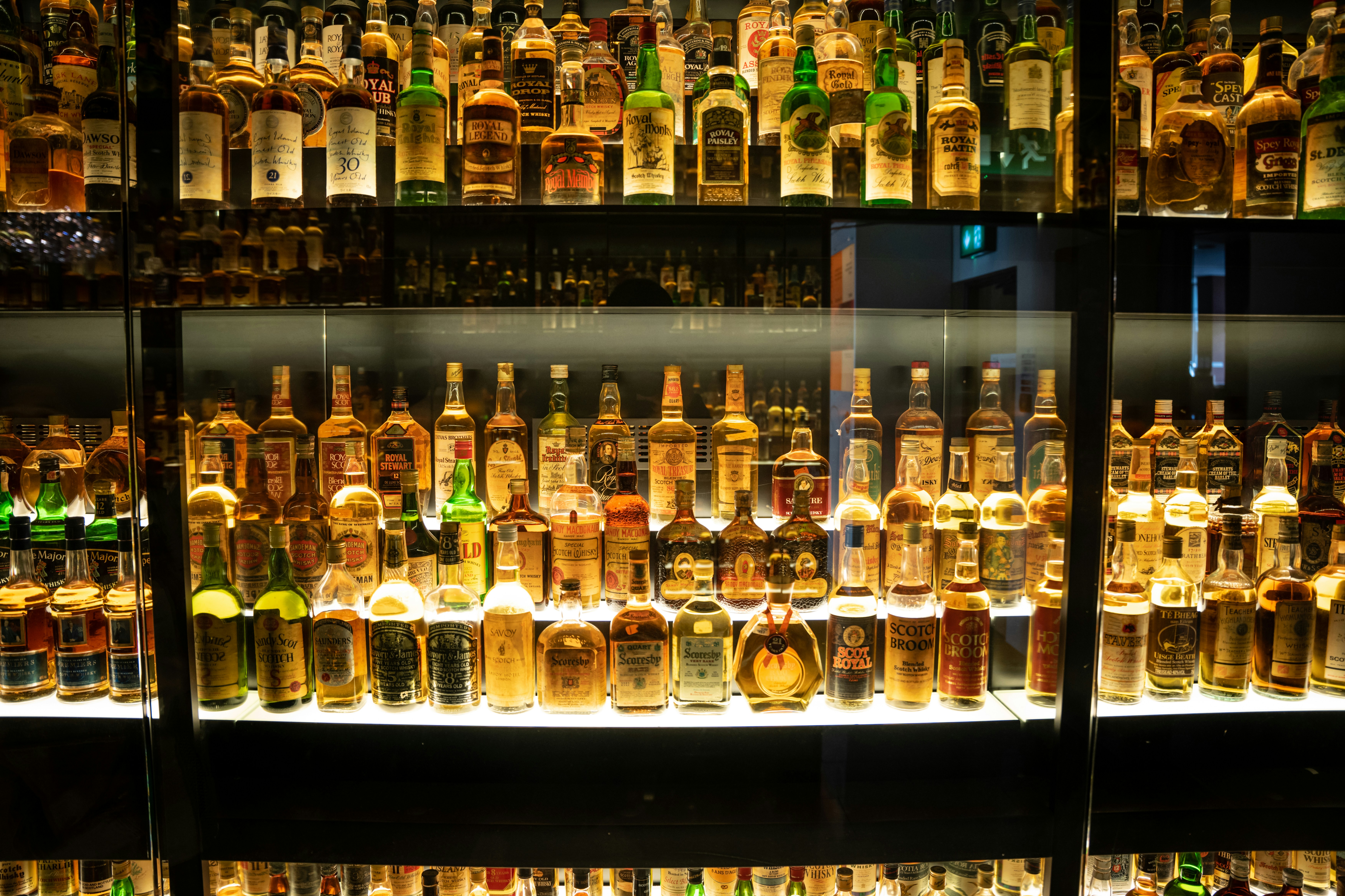 Many bottles of alcohol are on display in a glass case photo – Free ...