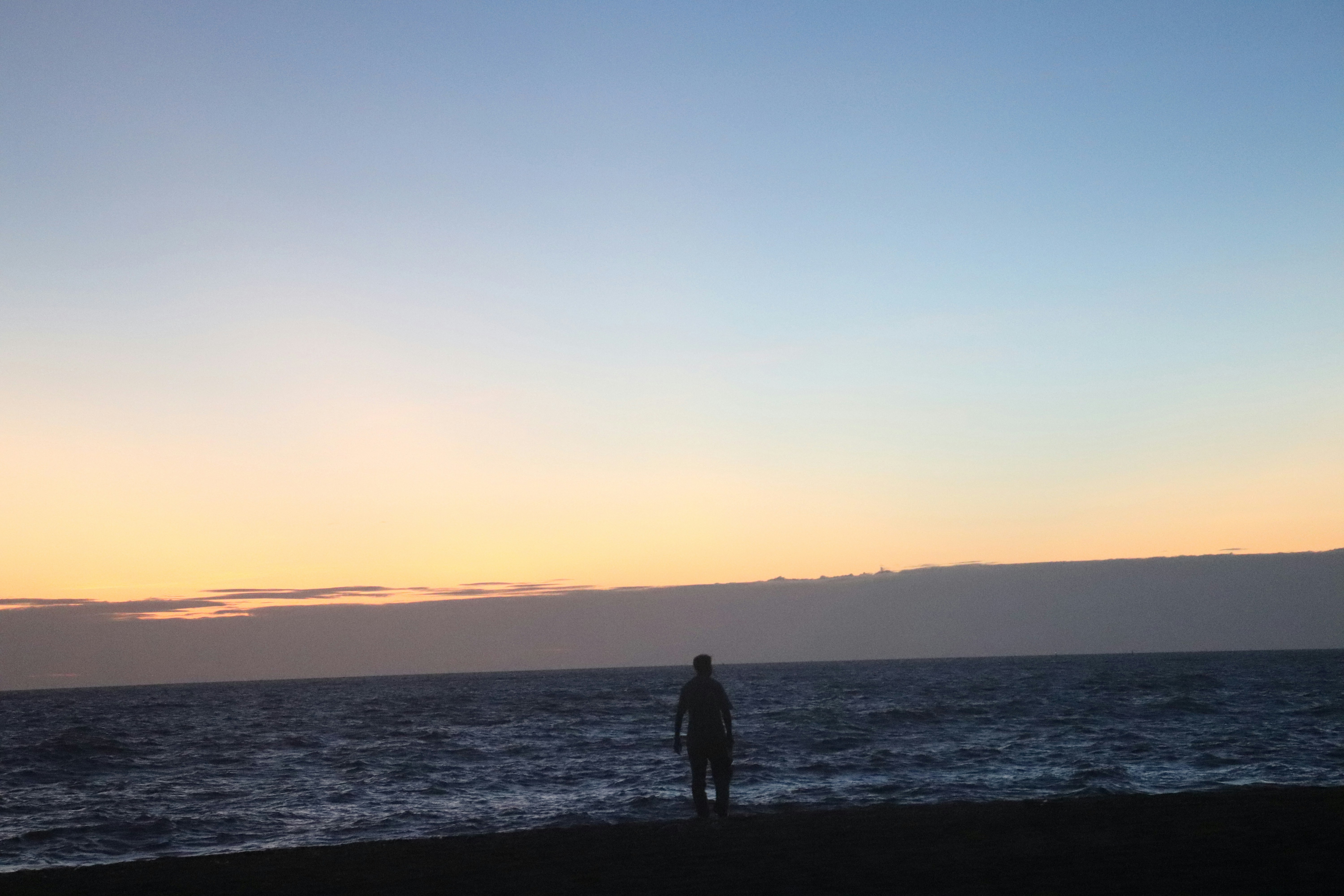 Solitary Silhouette at Dusk: A lone figure stands before a velvet horizon