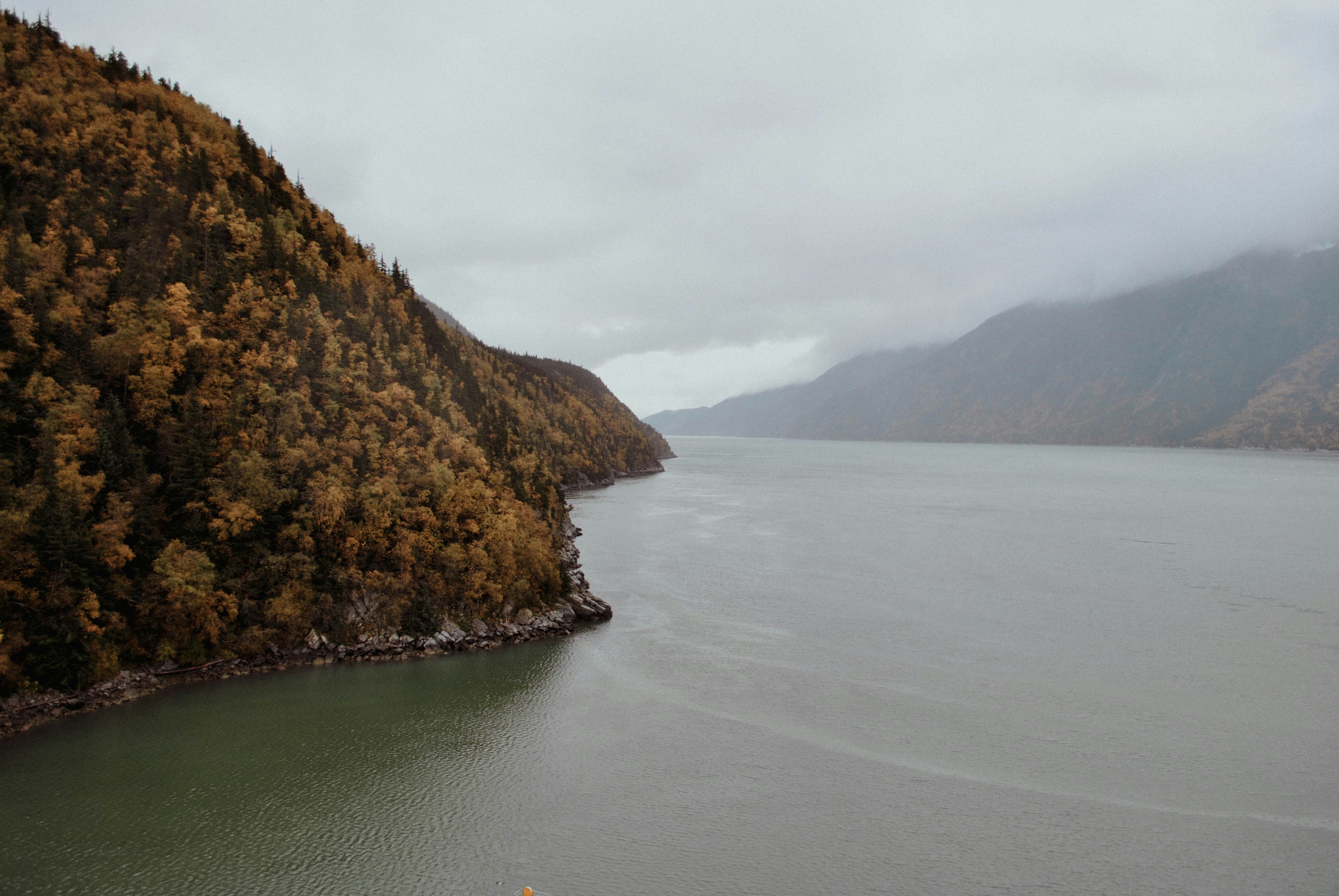 Amber-clad Hills Guard a Quiet Lake Beneath Misty Skies