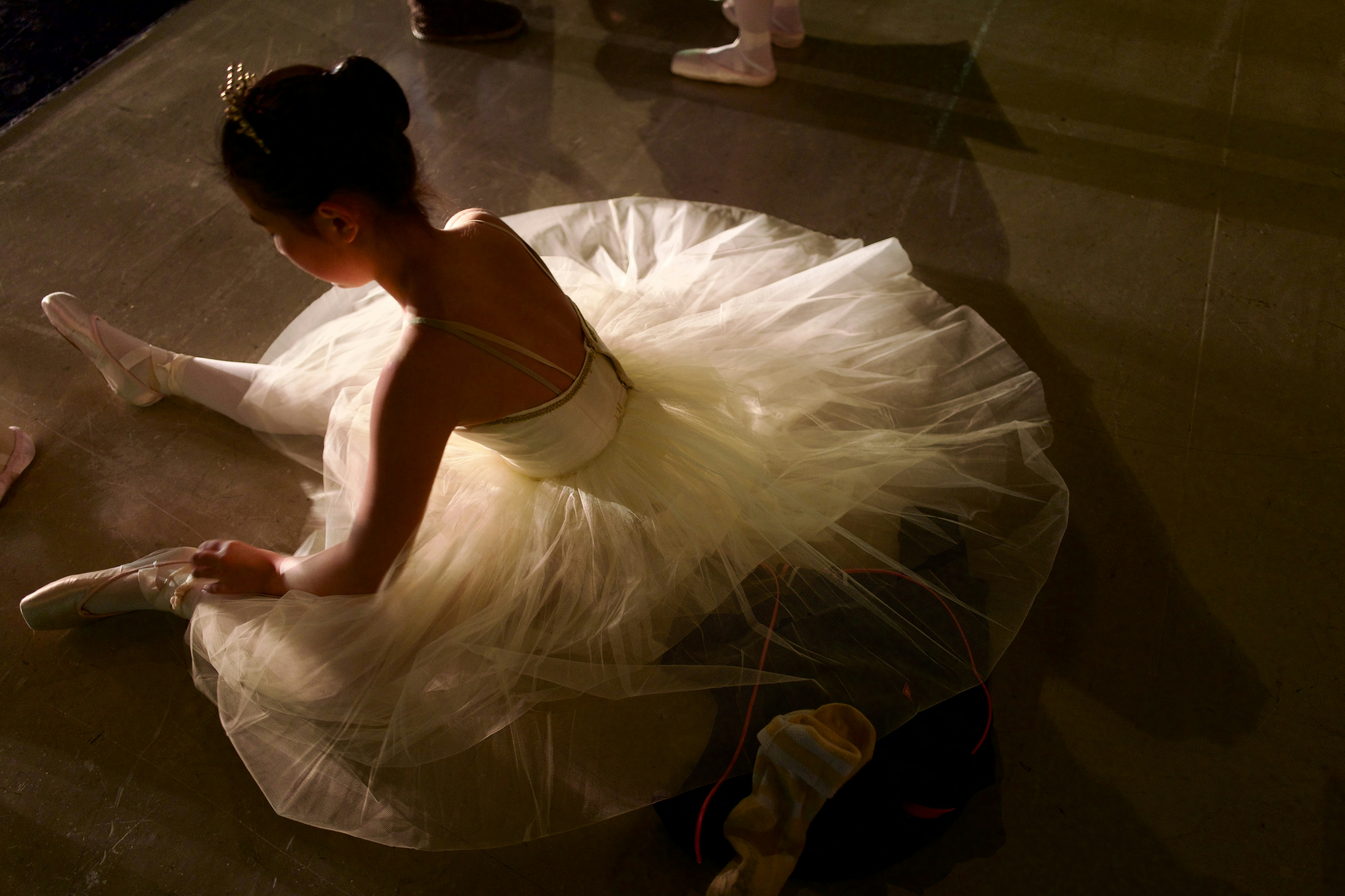 A young ballerina in a white tutu sitting on the floor photo – Free ...