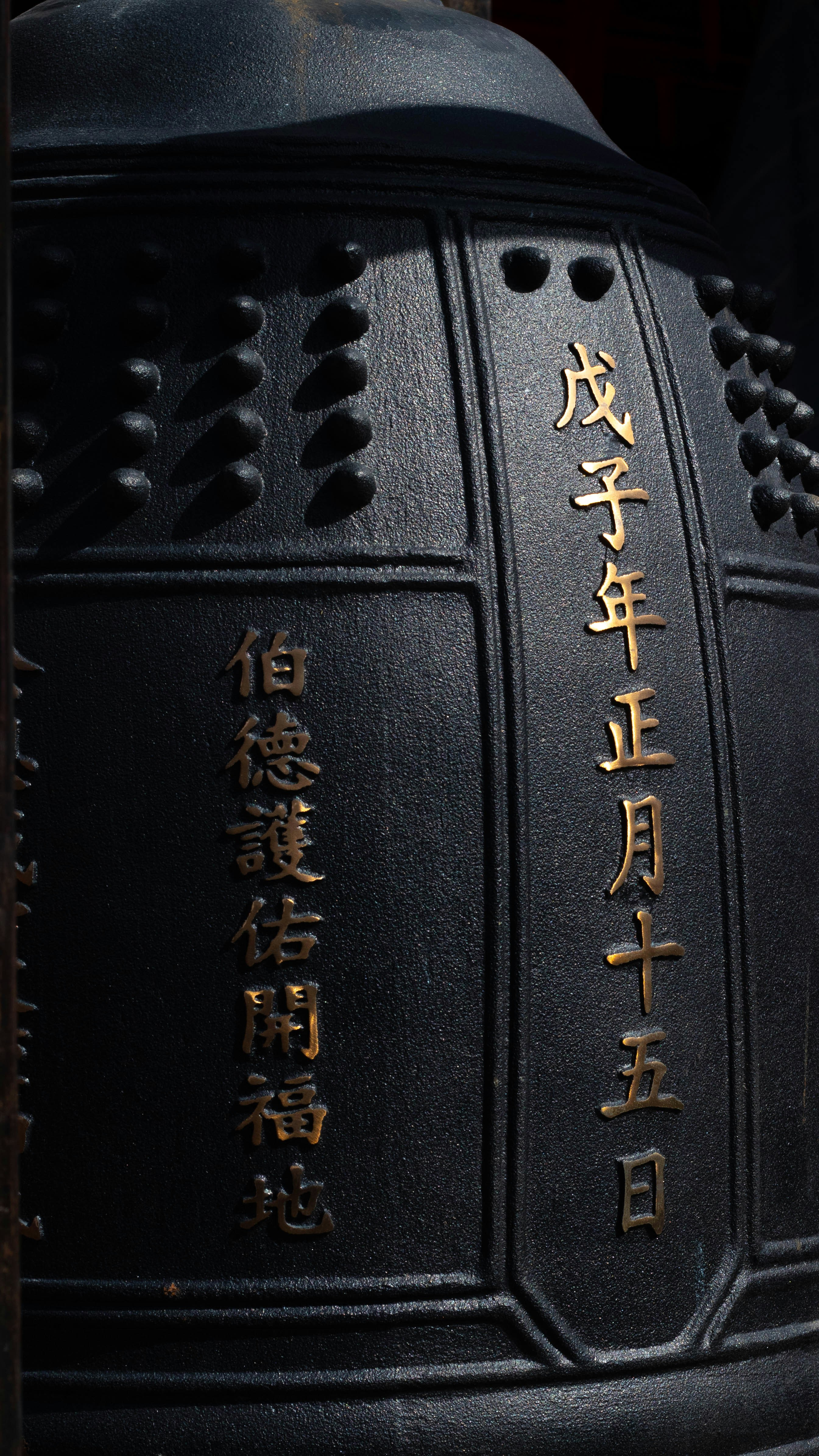 Golden Glyphs on Midnight Bell: Macro Portrait of Carved Chinese Script