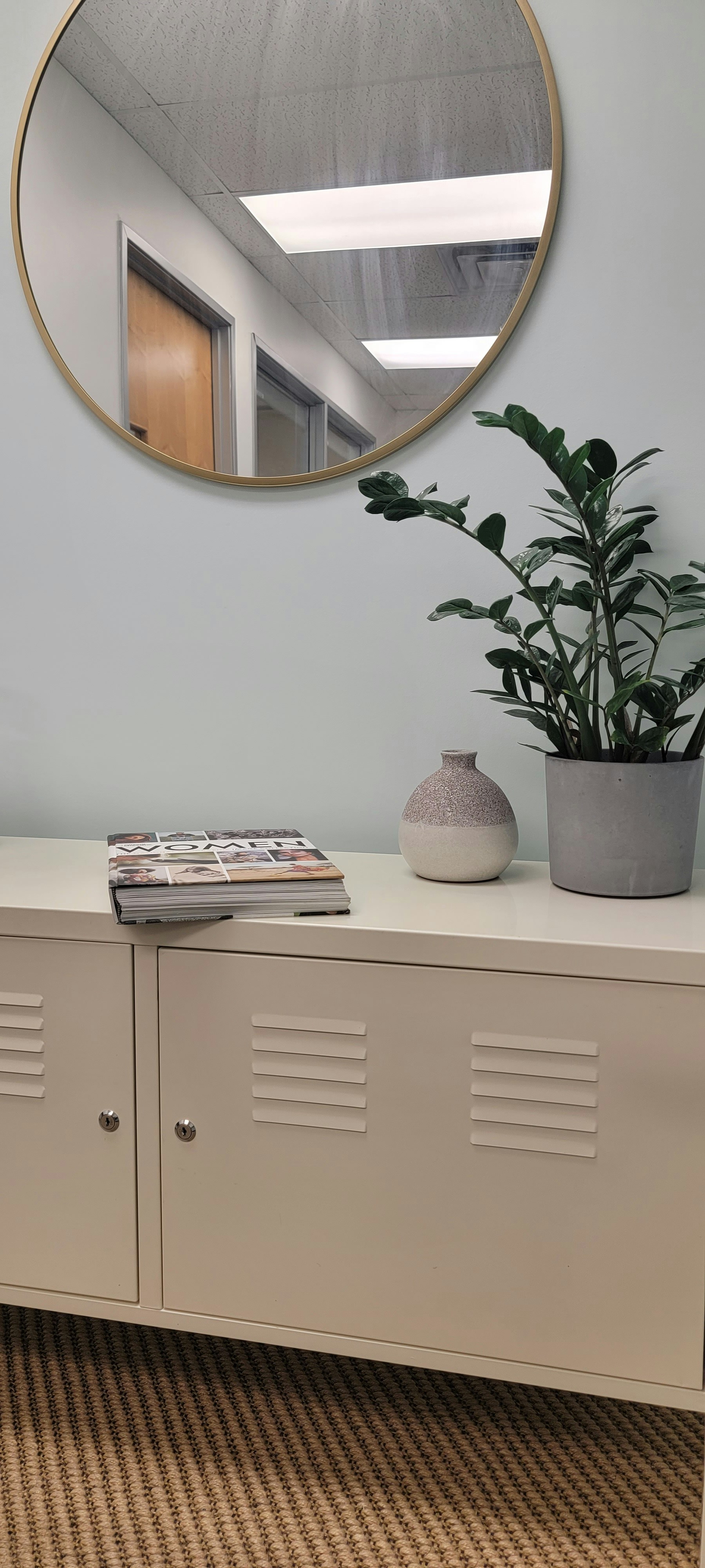 Circular Mirror Over Minimal Console: Plant, Vase, and Magazine Quietude