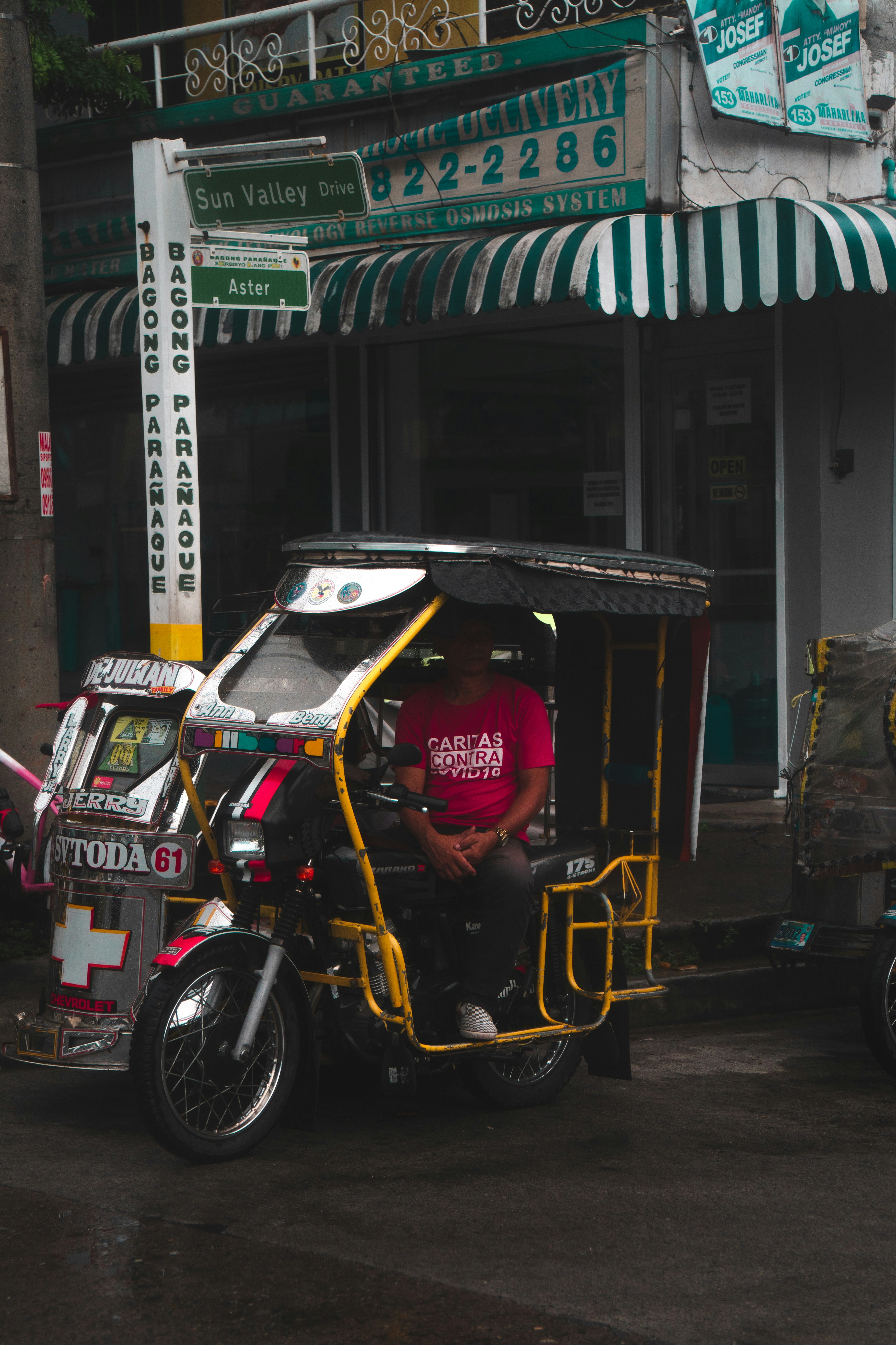 Yellow Pedicab Under a Green Striped Awning: Street Portrait on a Quiet Corner