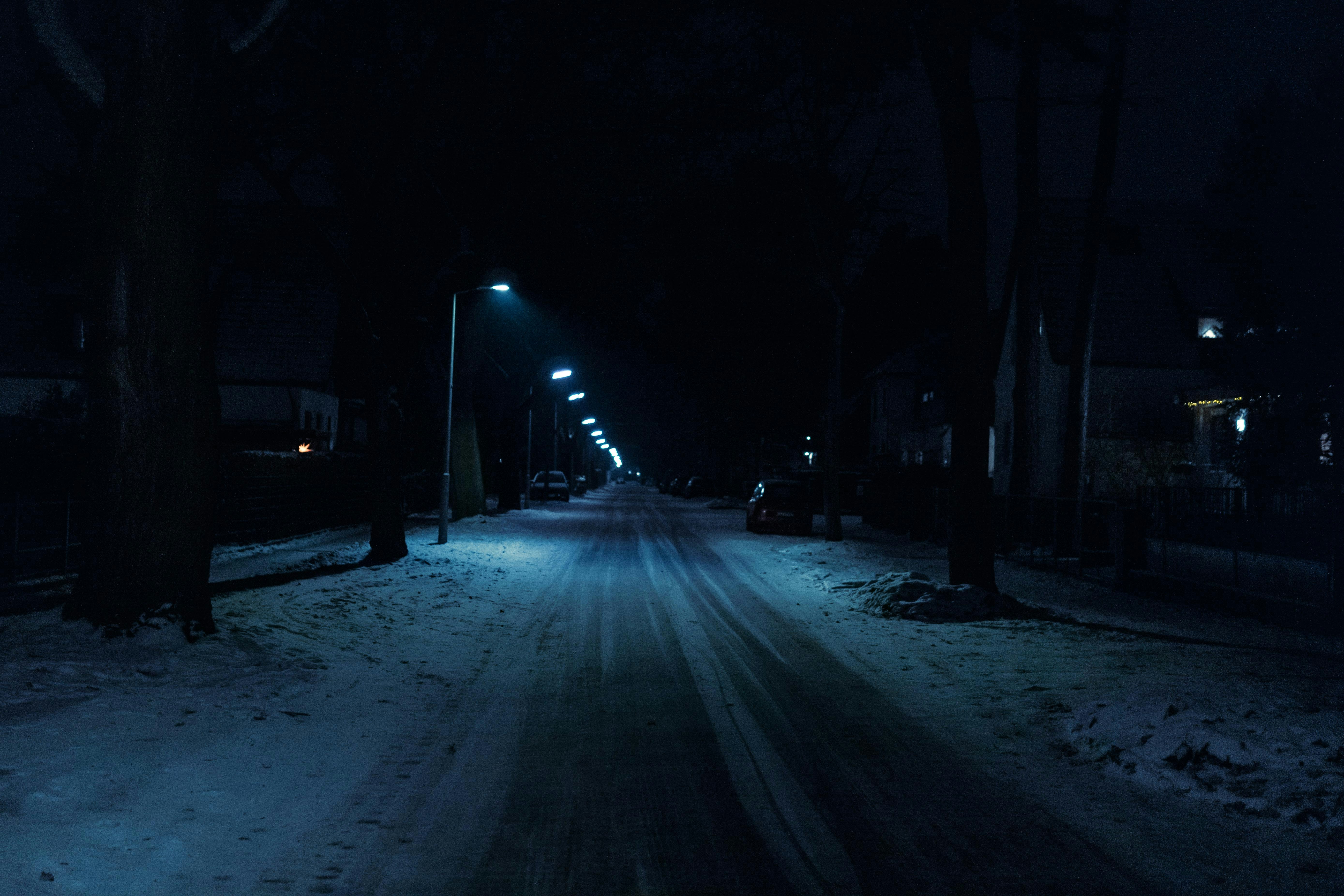 A dark street at night with snow on the ground photo – Free Car Image ...