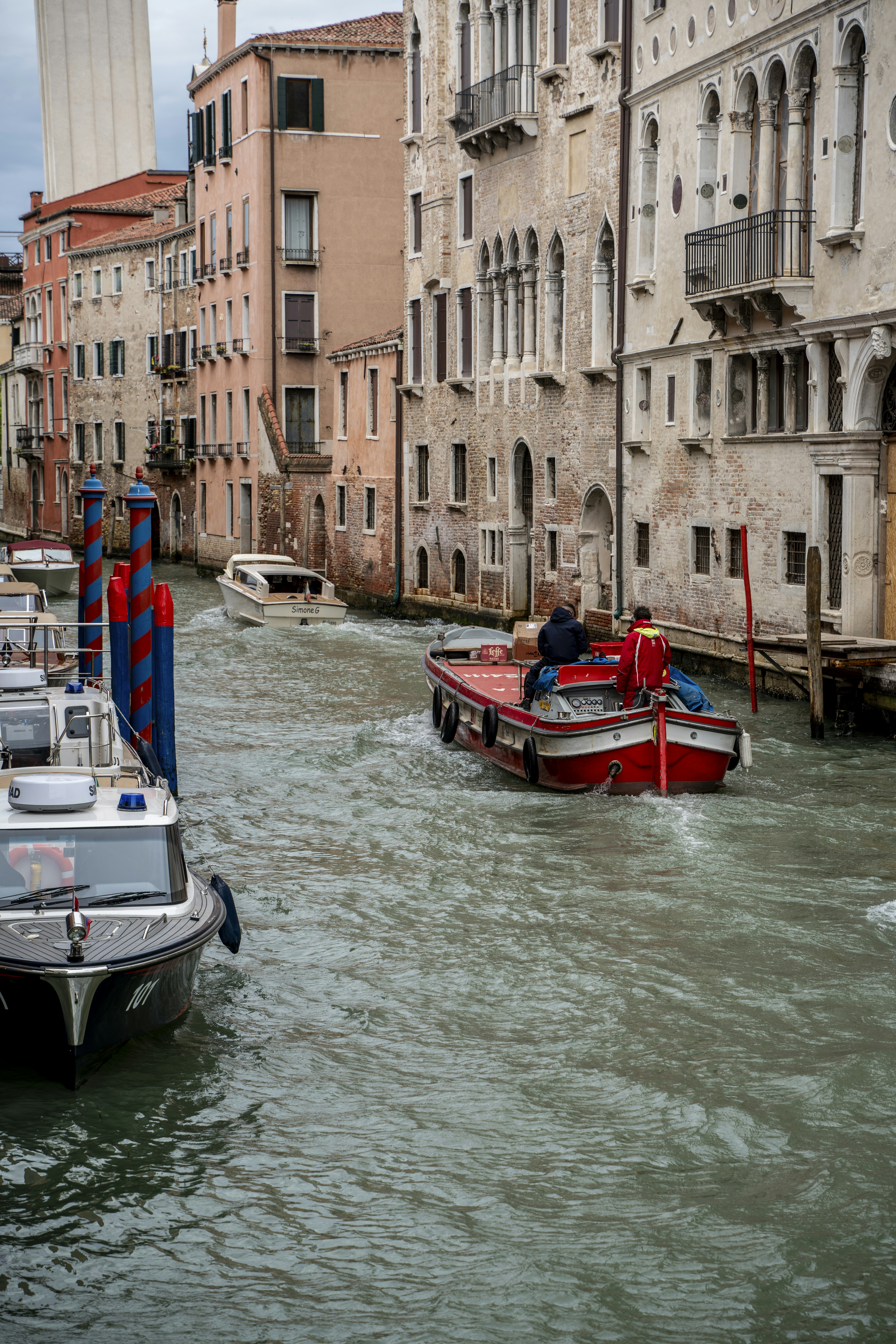 Red Boat Glide Between Weathered Palazzos on a Venetian Channel