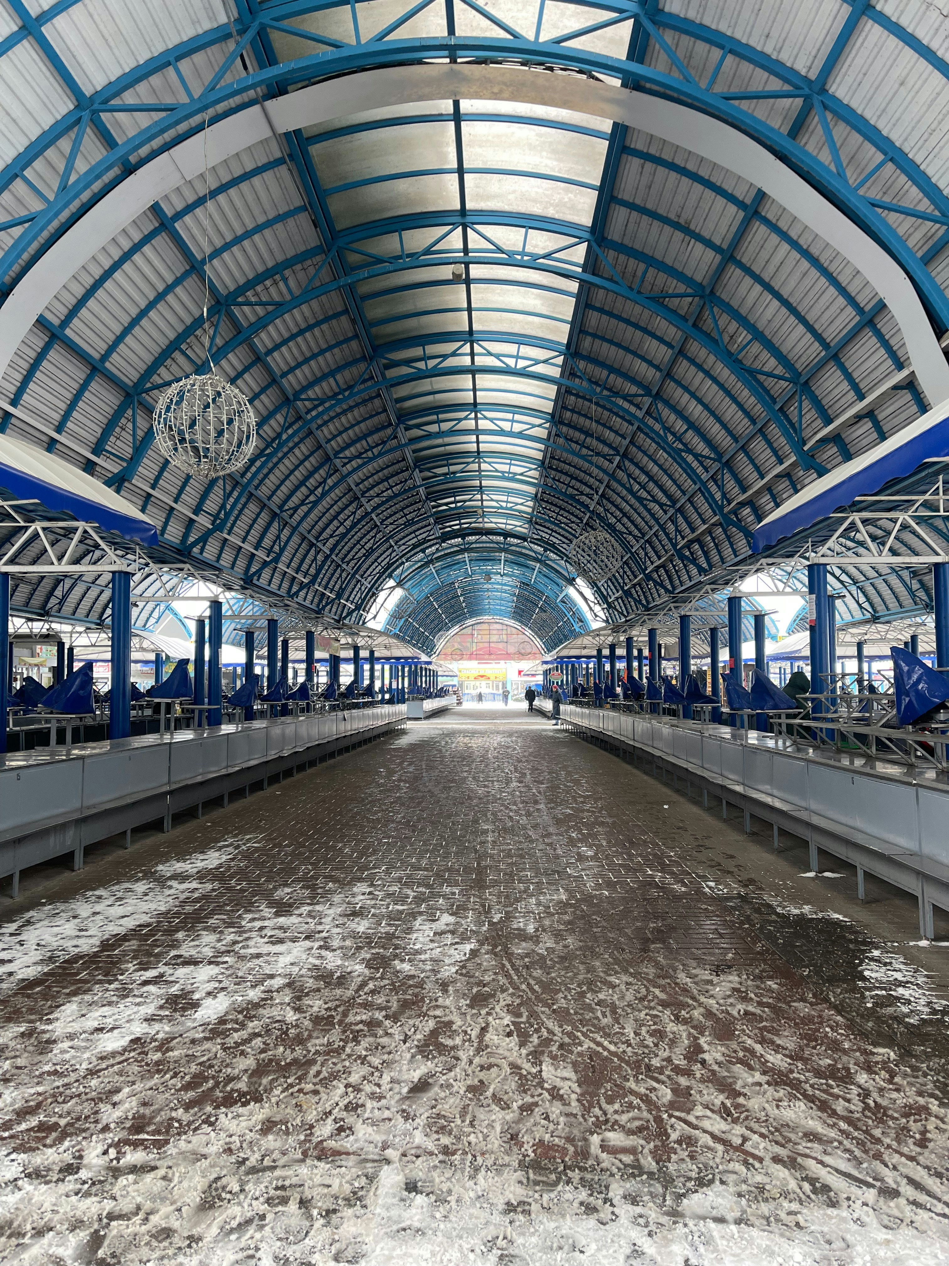 Vanishing Aisle Under a Blue Arch: Snow-Covered Market Hall Recedes to Light