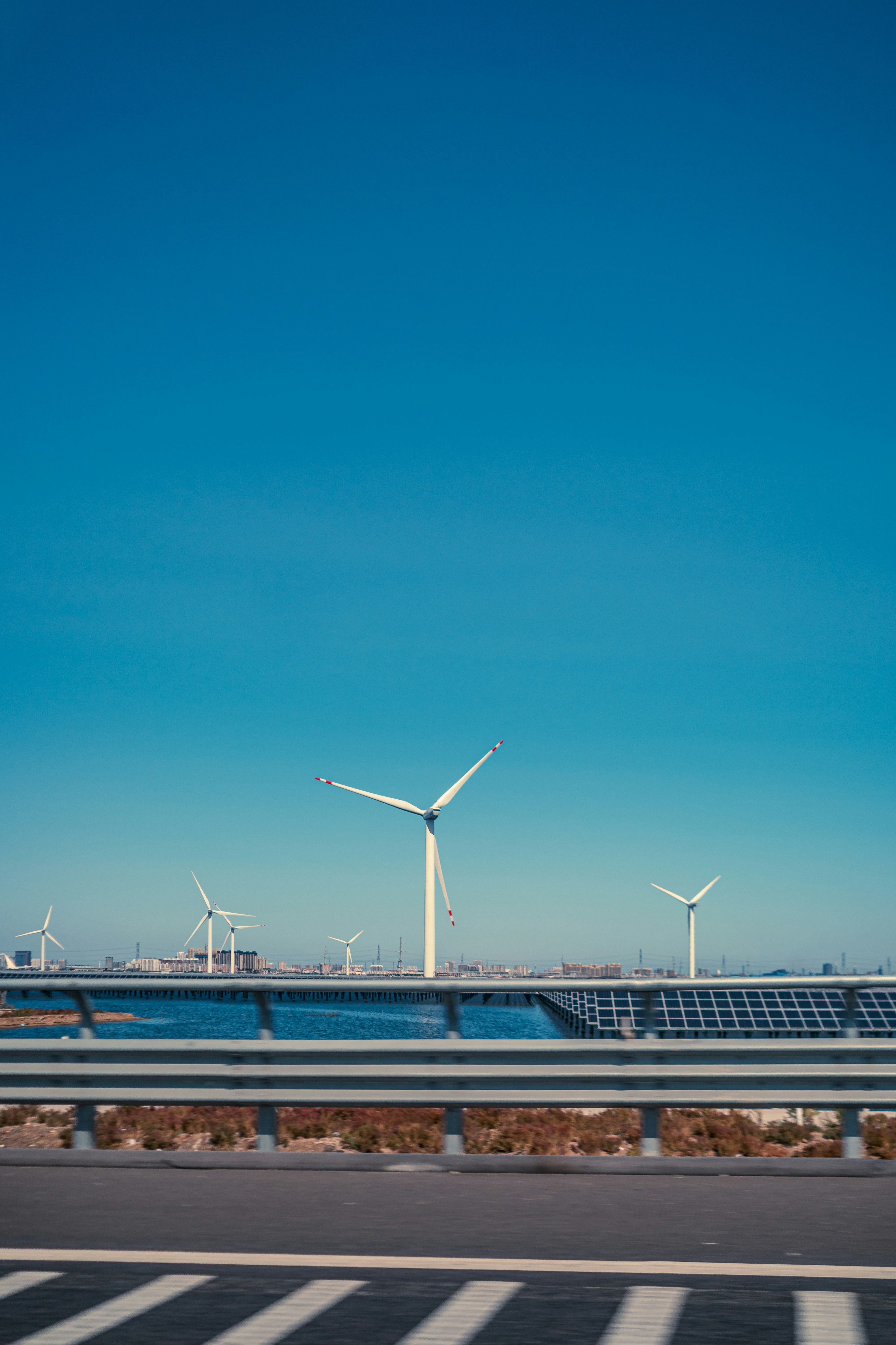 A car driving down a highway past wind turbines photo – Free Machine ...