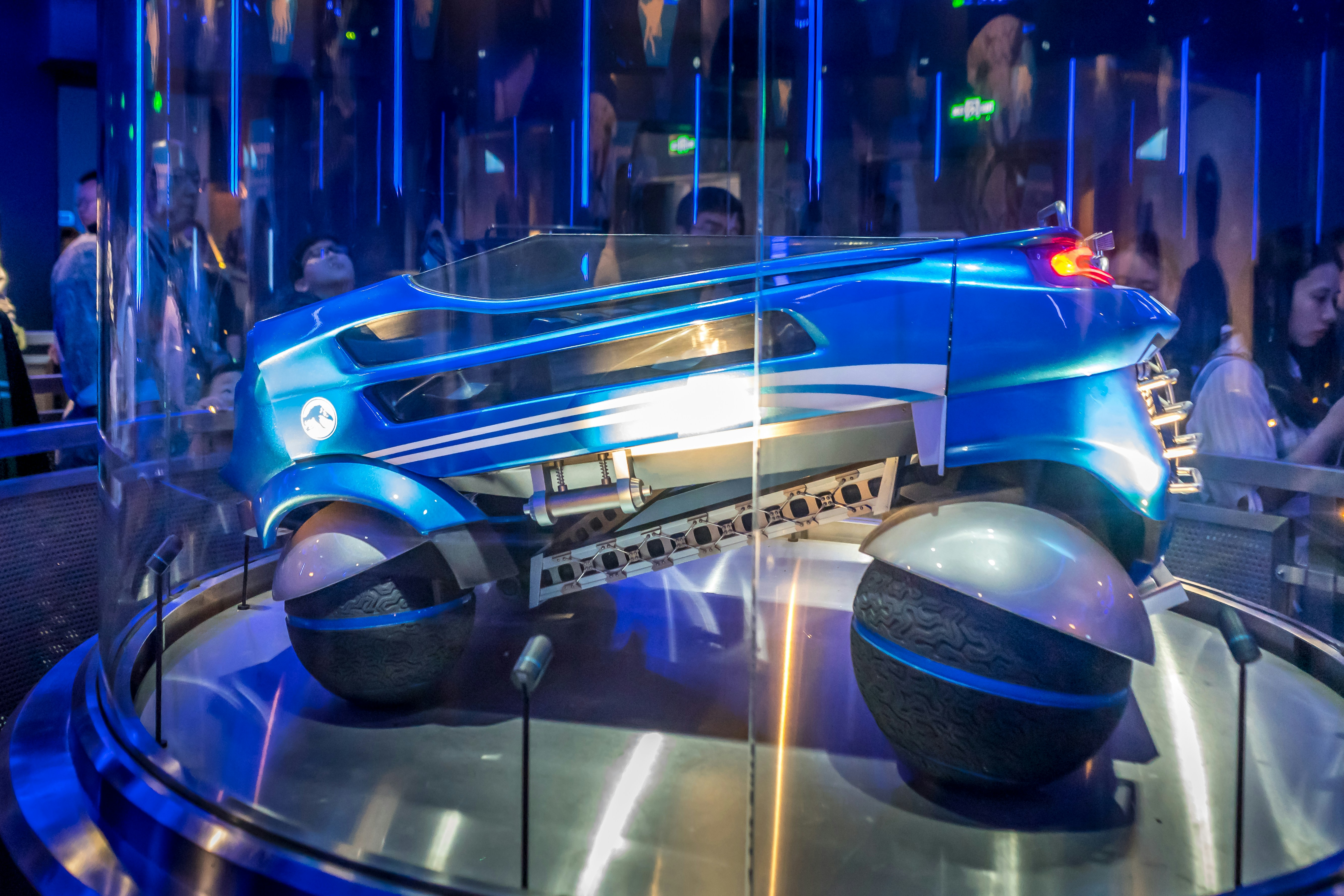 a blue car is on display in a glass case