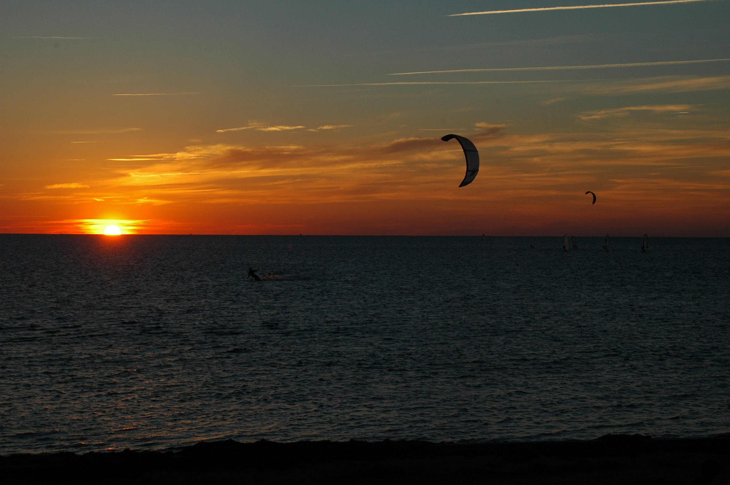 A couple of kites flying over a body of water photo – Free Outer banks ...