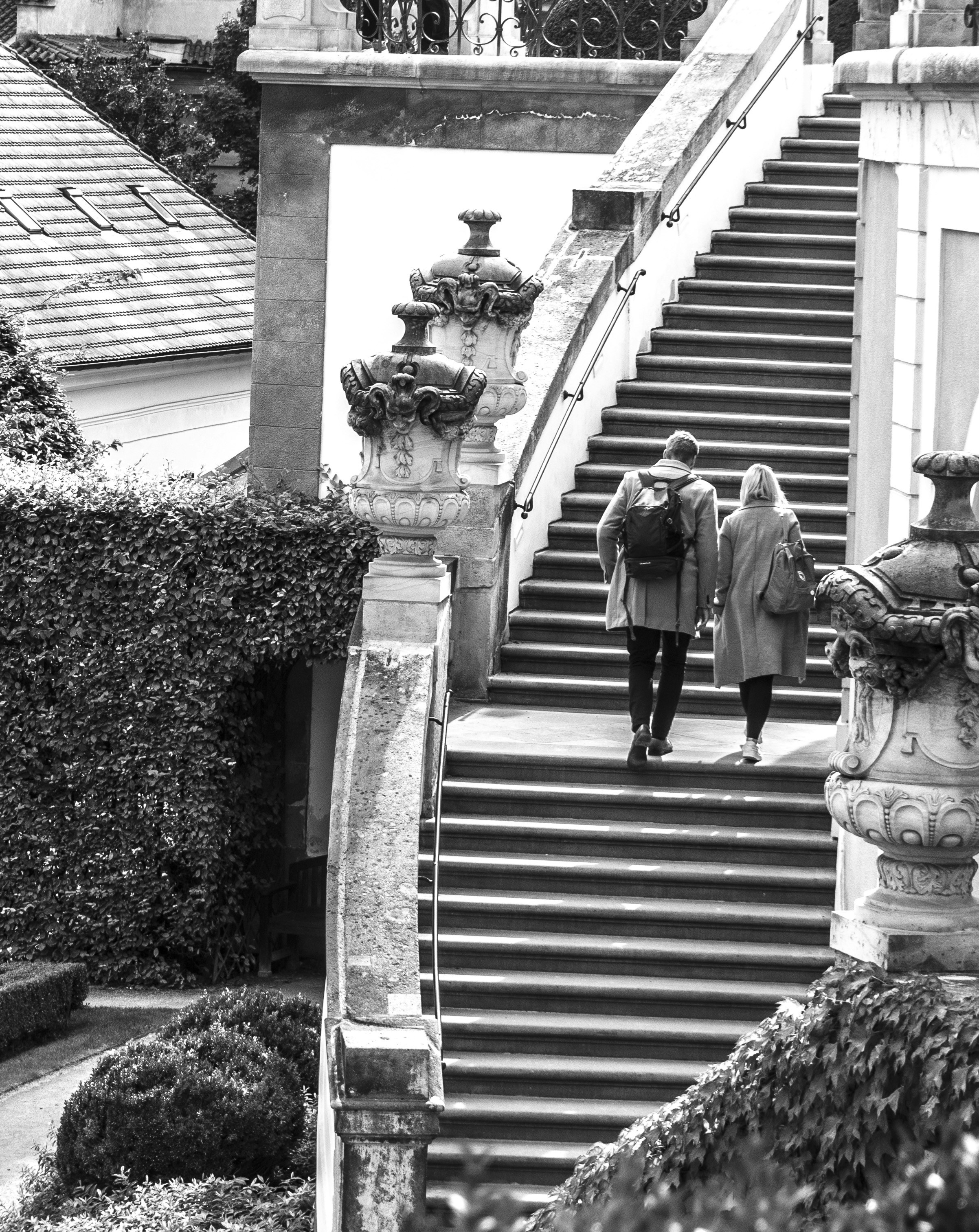 Grayscale Ascent: Two Travelers on an Ornate Staircase