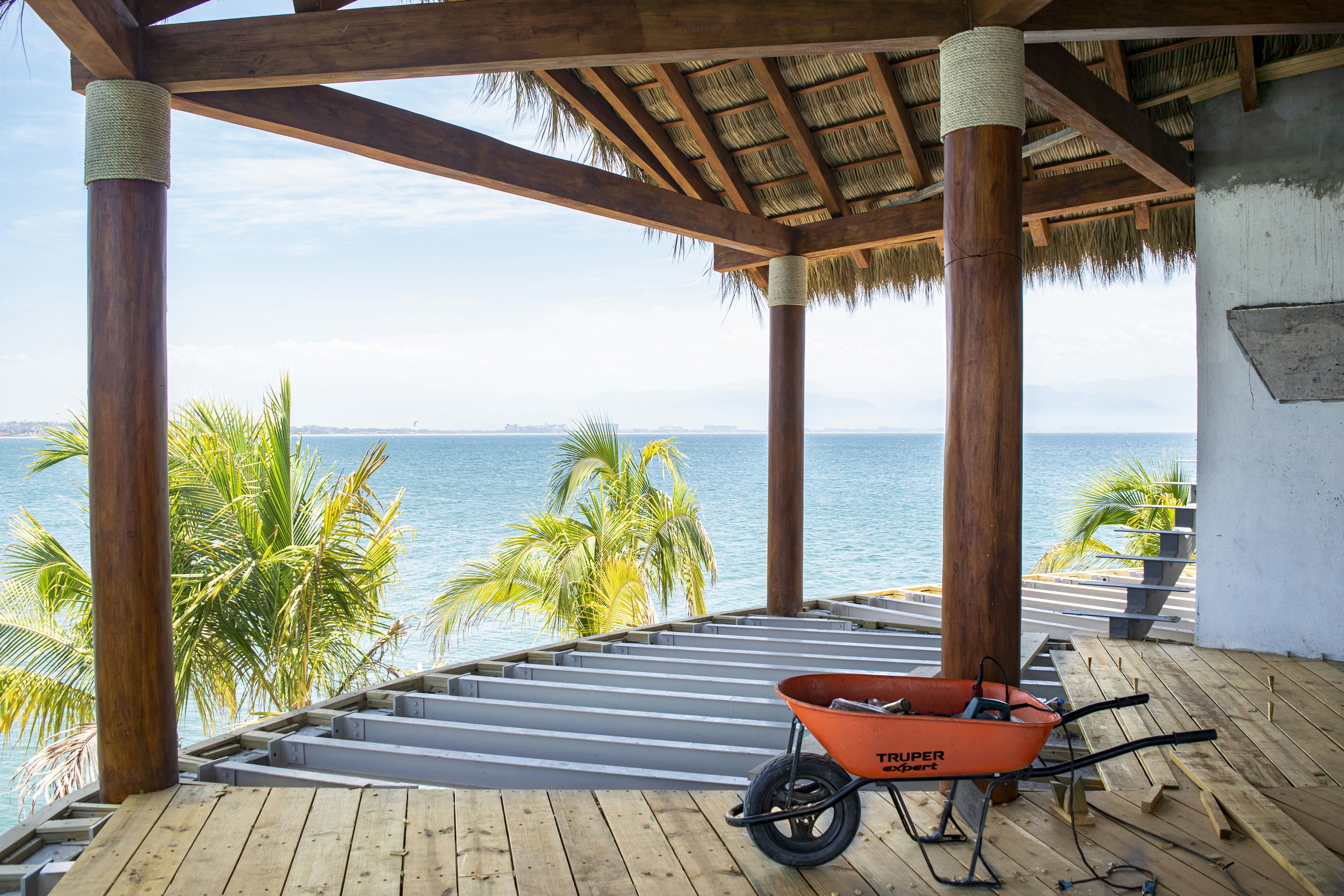 A wheelbarrow is sitting on a deck near the ocean photo – Free Beach ...