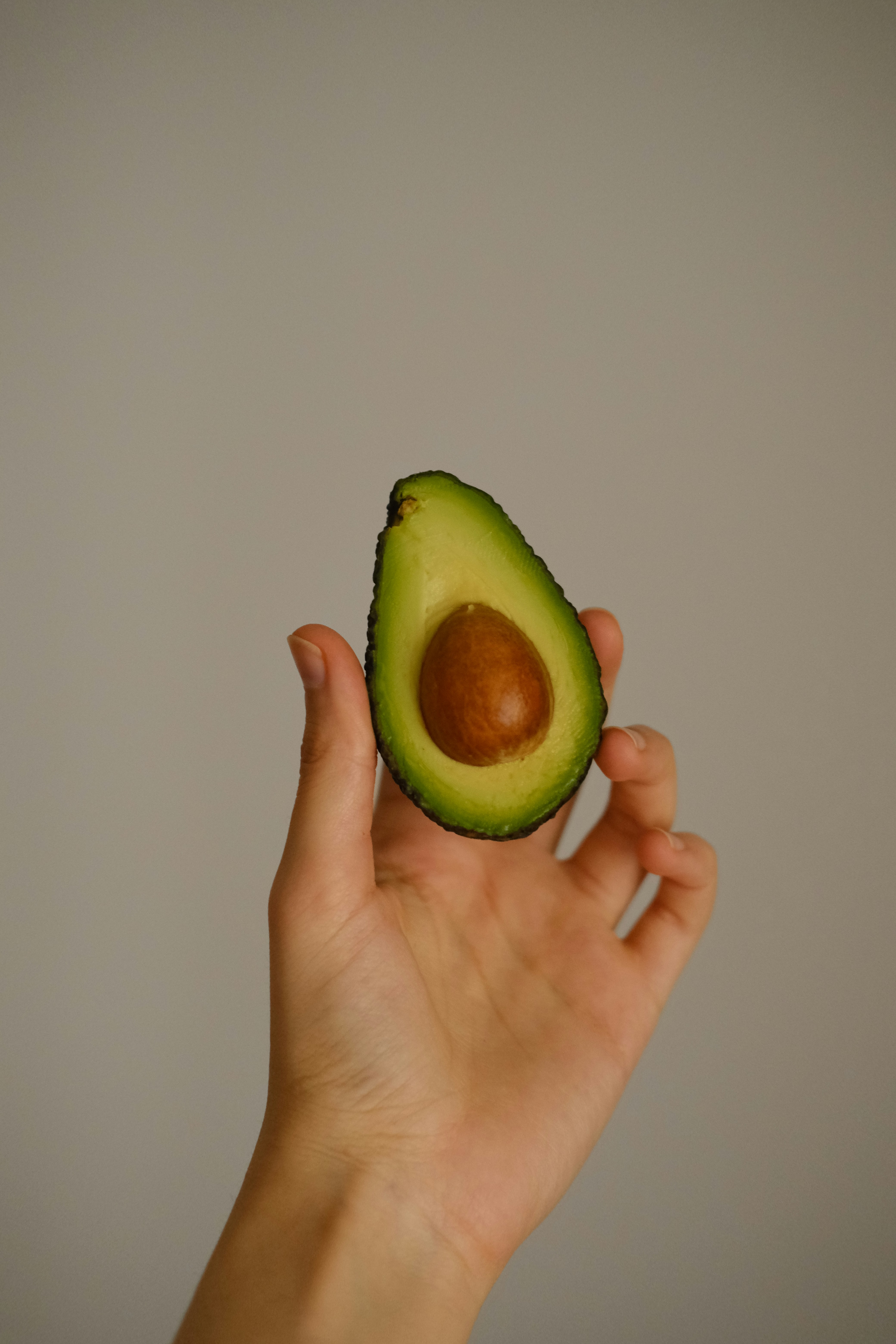 Palm-Held Avocado: A Halved Green Moment Against a Quiet Backdrop