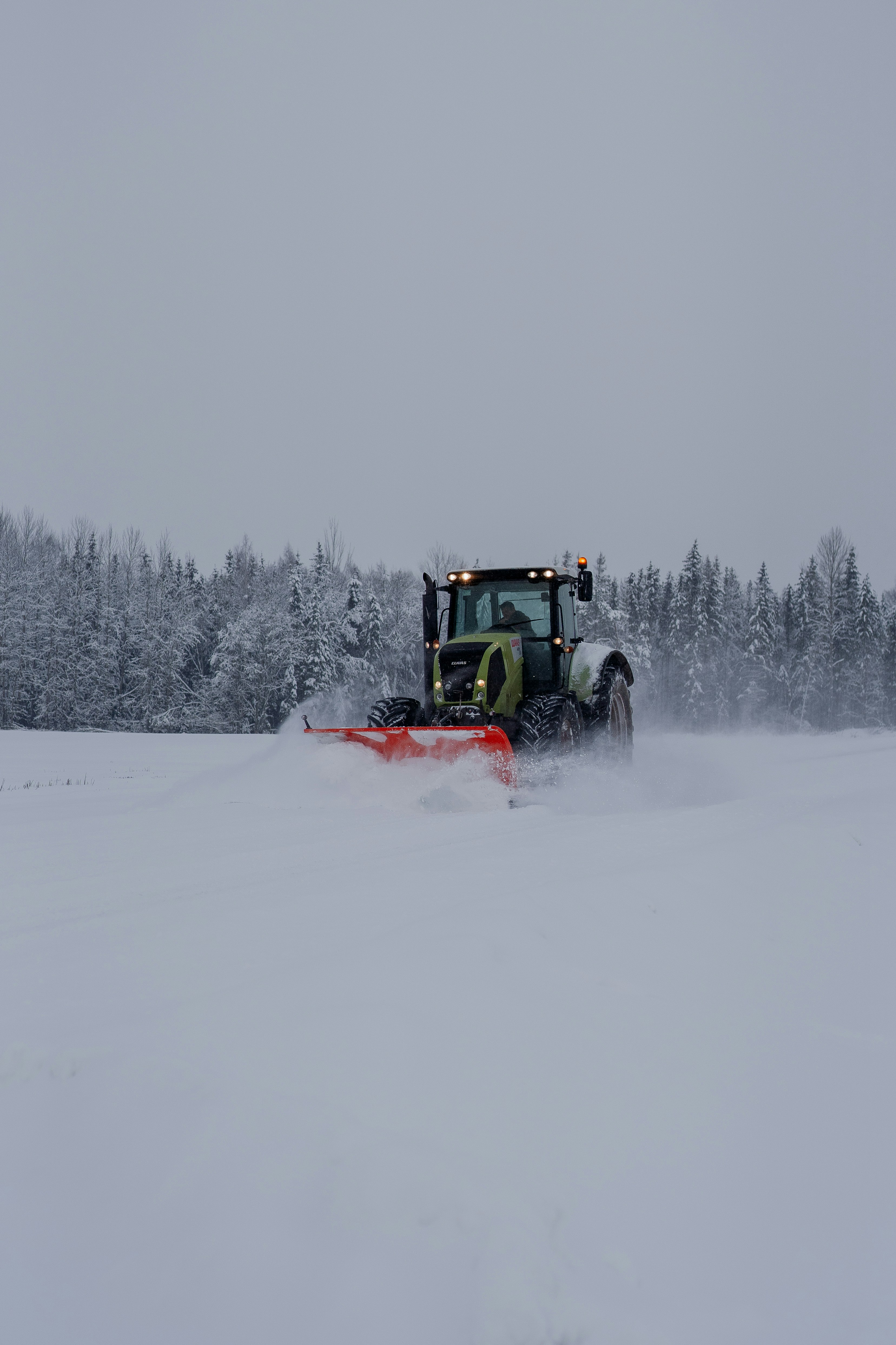 A tractor plows through a snow covered field photo – Free Latvia Image ...