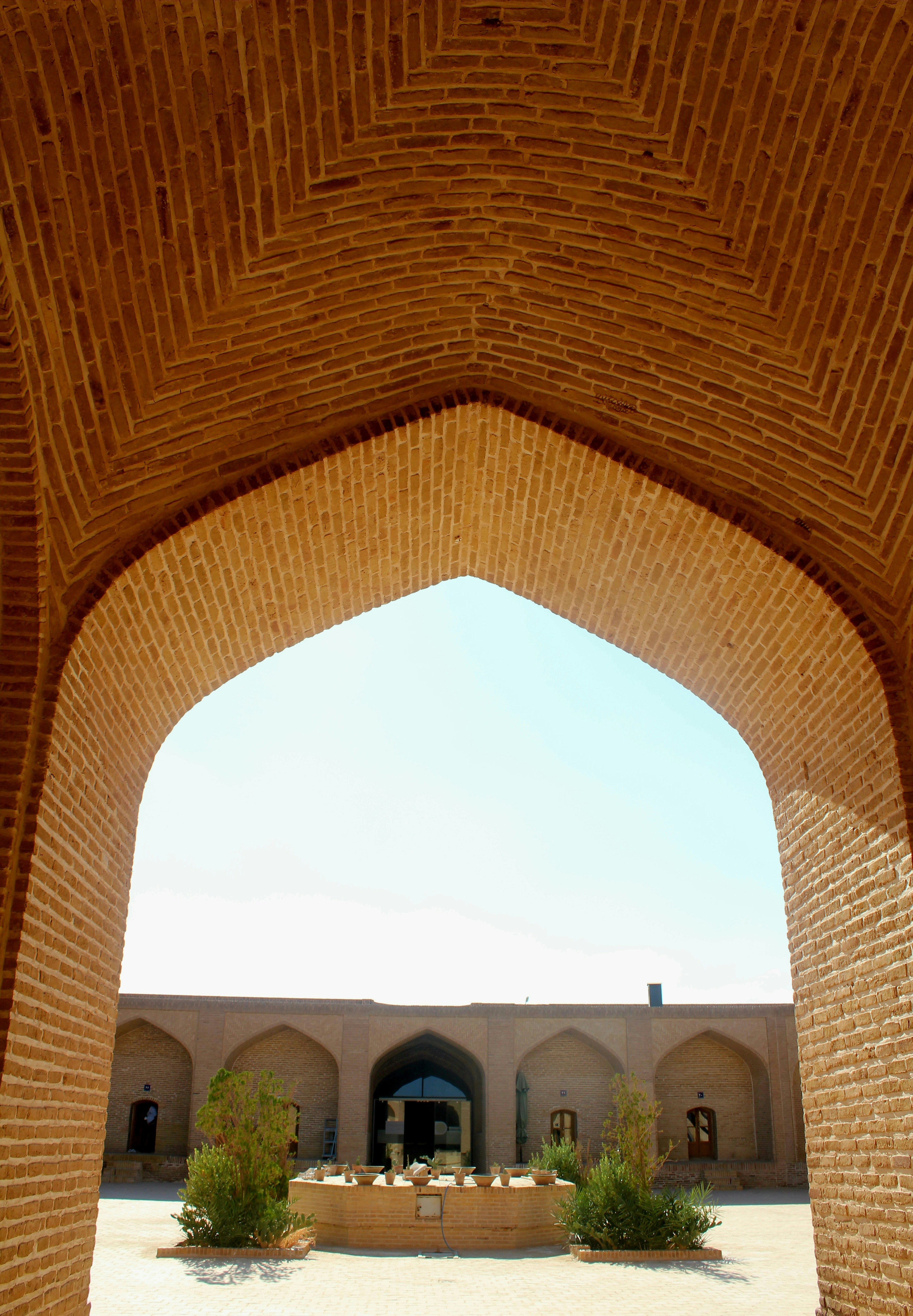 Brick Archway to a Sunlit Courtyard: Circular Fountain Framed by Arches