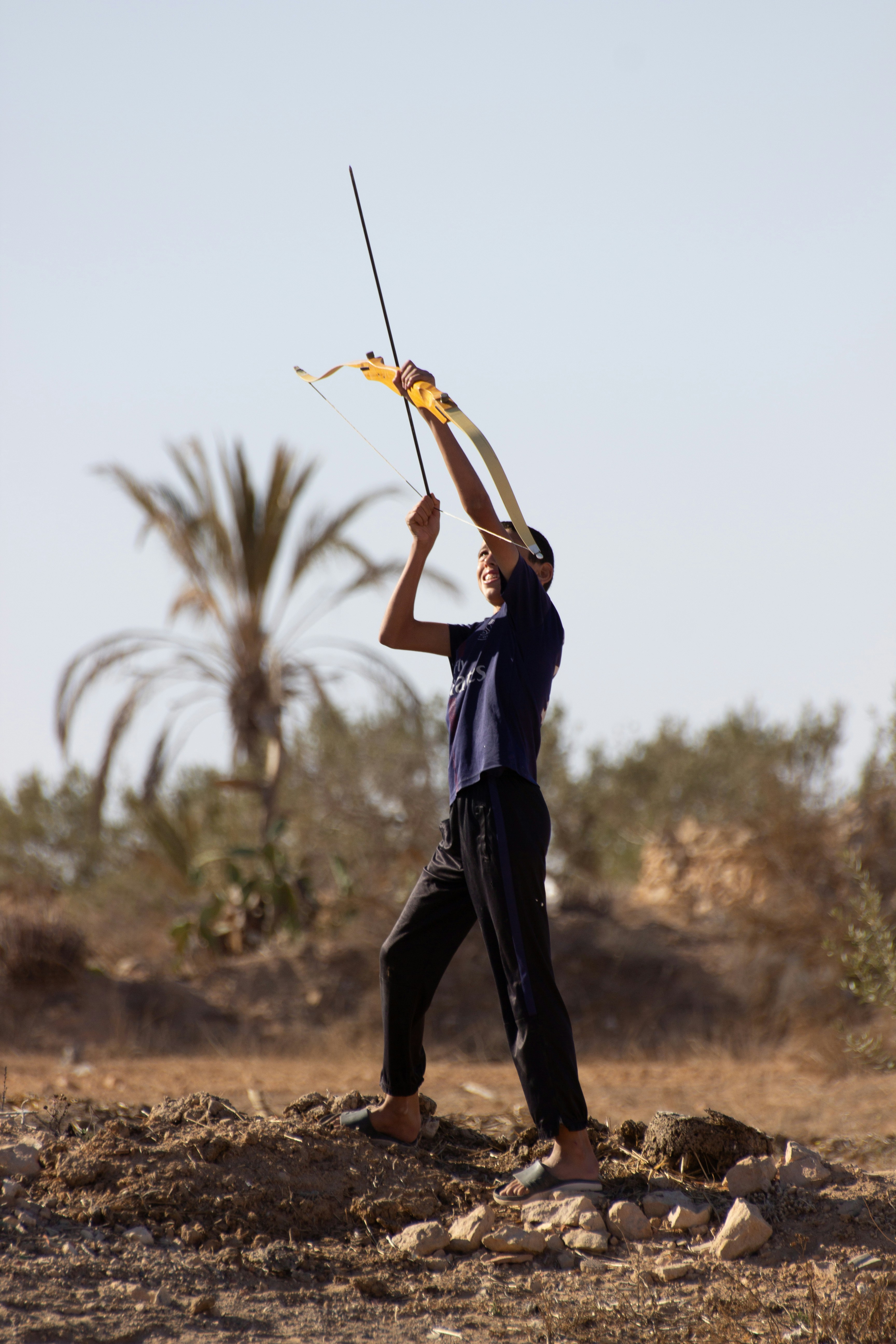 Archery in the Dust: A Solo Archer Reaches Skyward with Ribbon and Bow