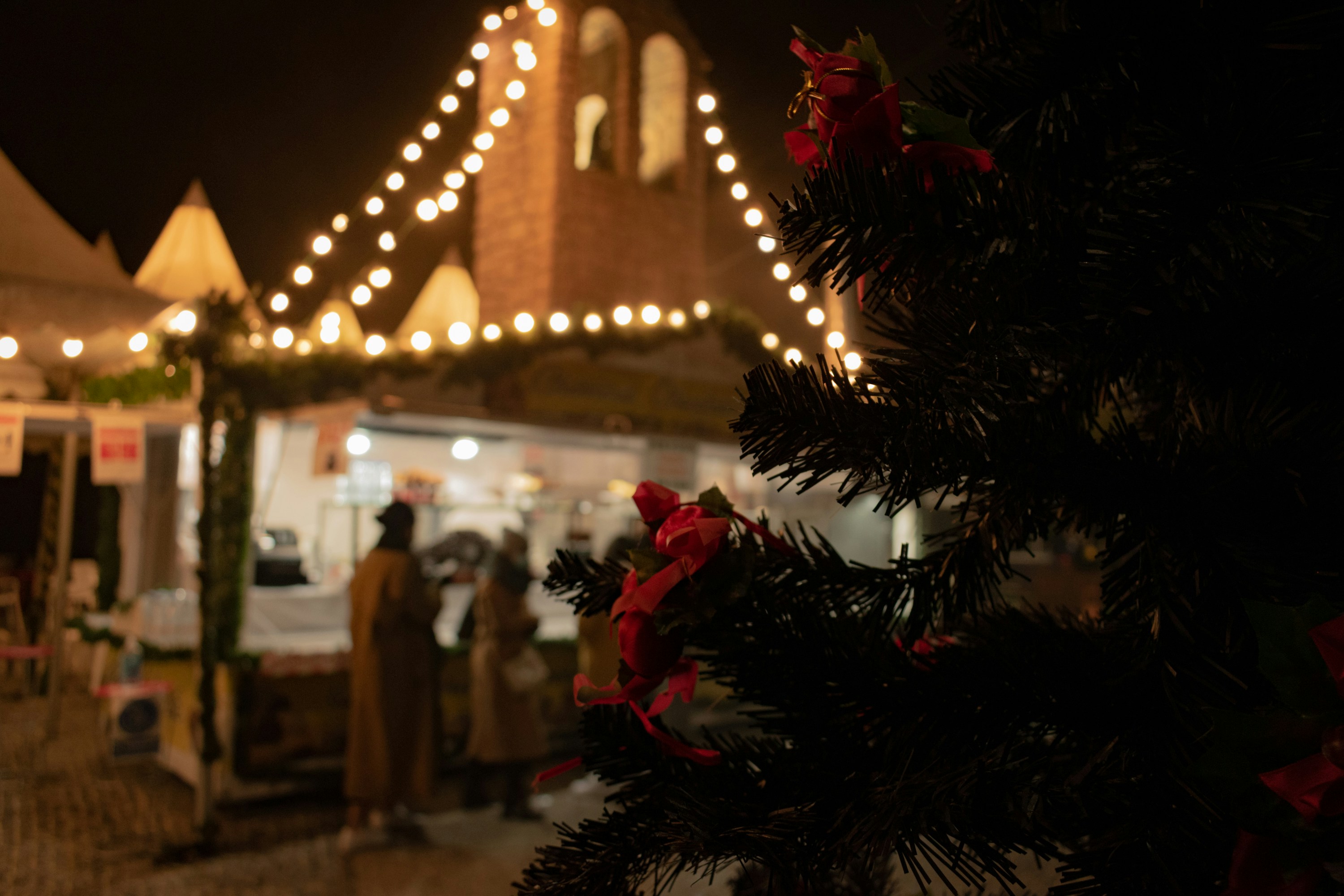 Right-Edge Christmas Tree Framed by Night-Market Glow