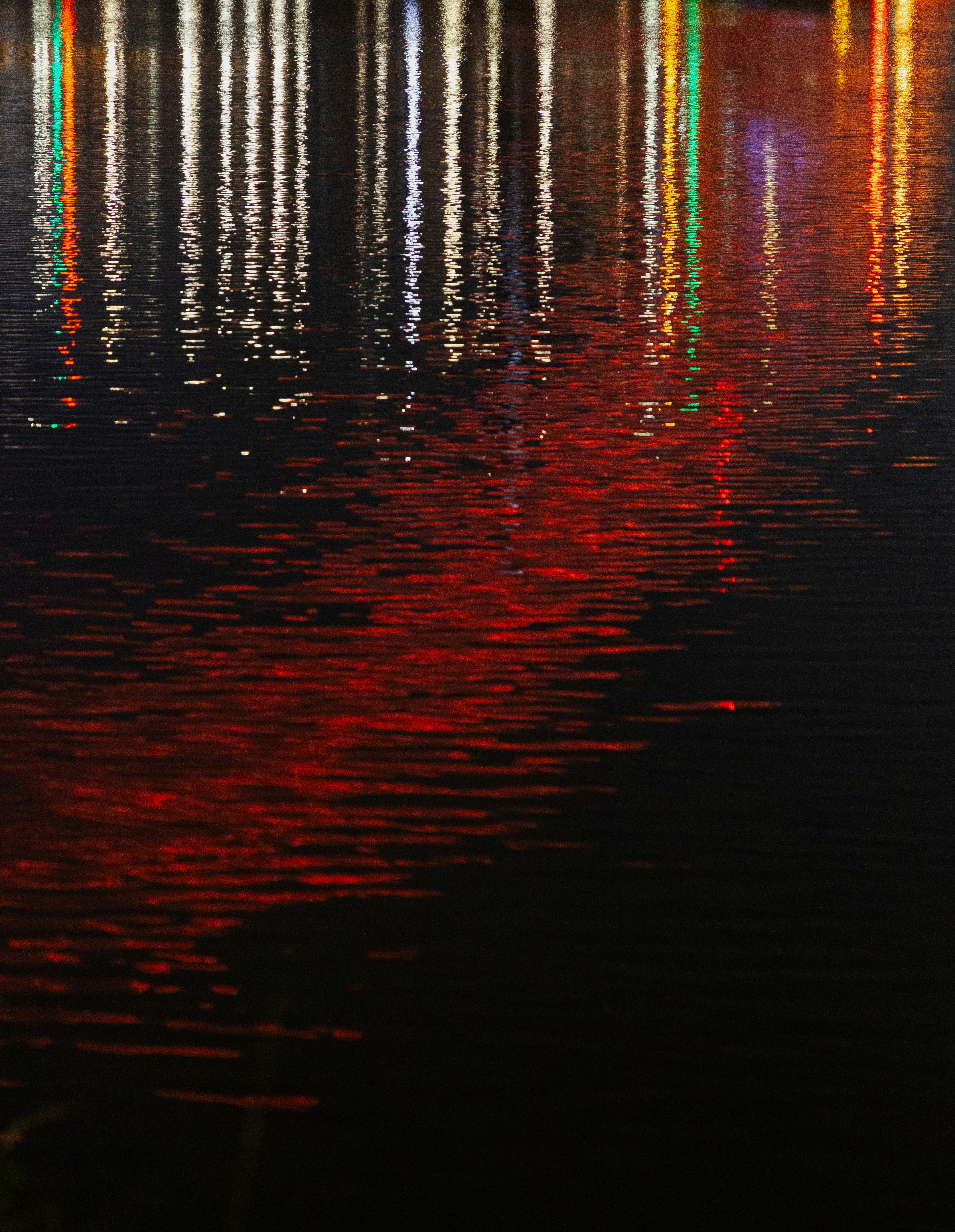 Red Echoes and Neon Streaks Across Night Water
