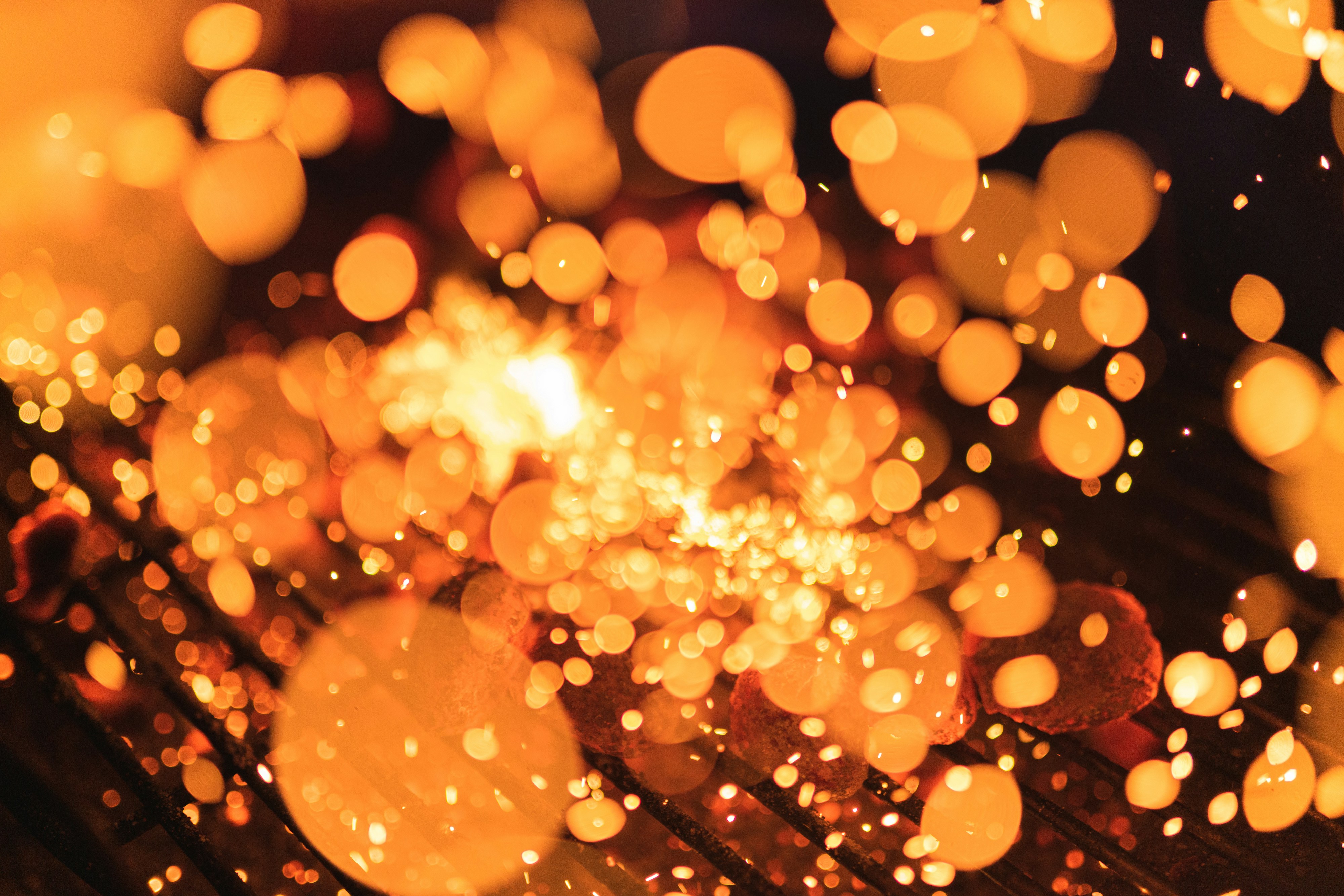 Bright orange sparks cascade in dynamic motion against a dark background.