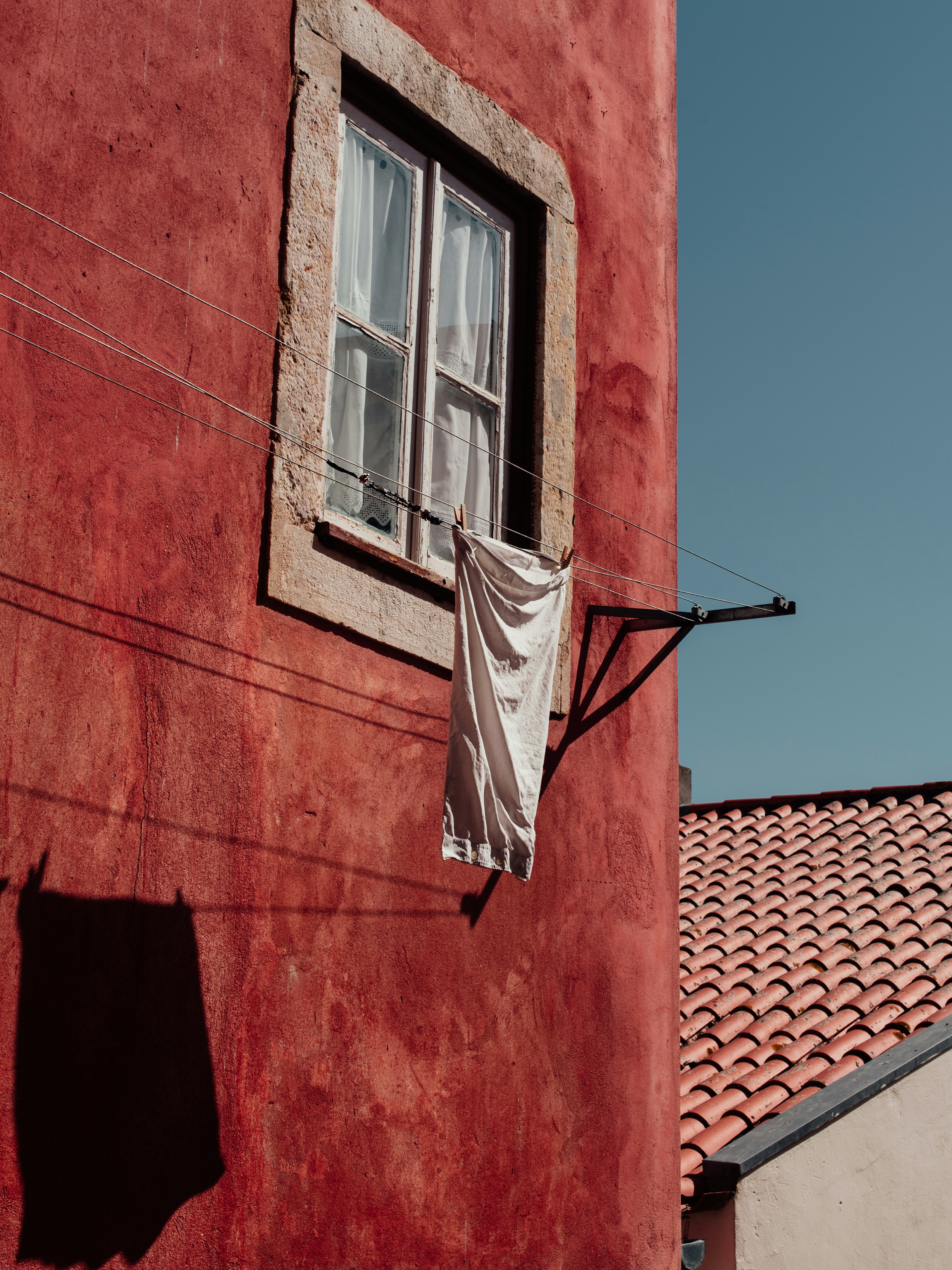 Crimson Facade with Laundry on a Wire Beneath a Slanted Tile Roof