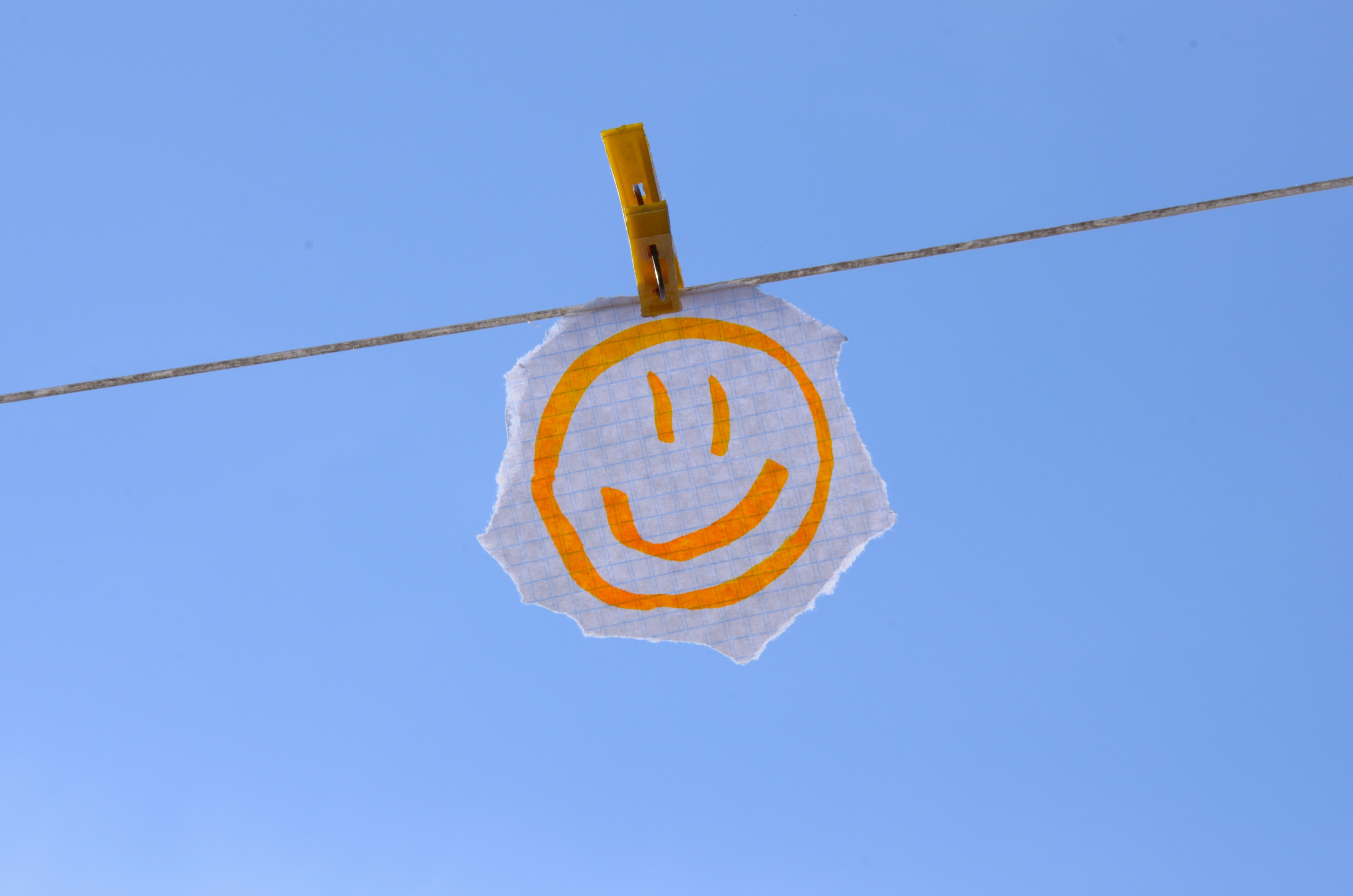 A smiley face sign hanging on a clothes line photo – Free Blue Image on ...