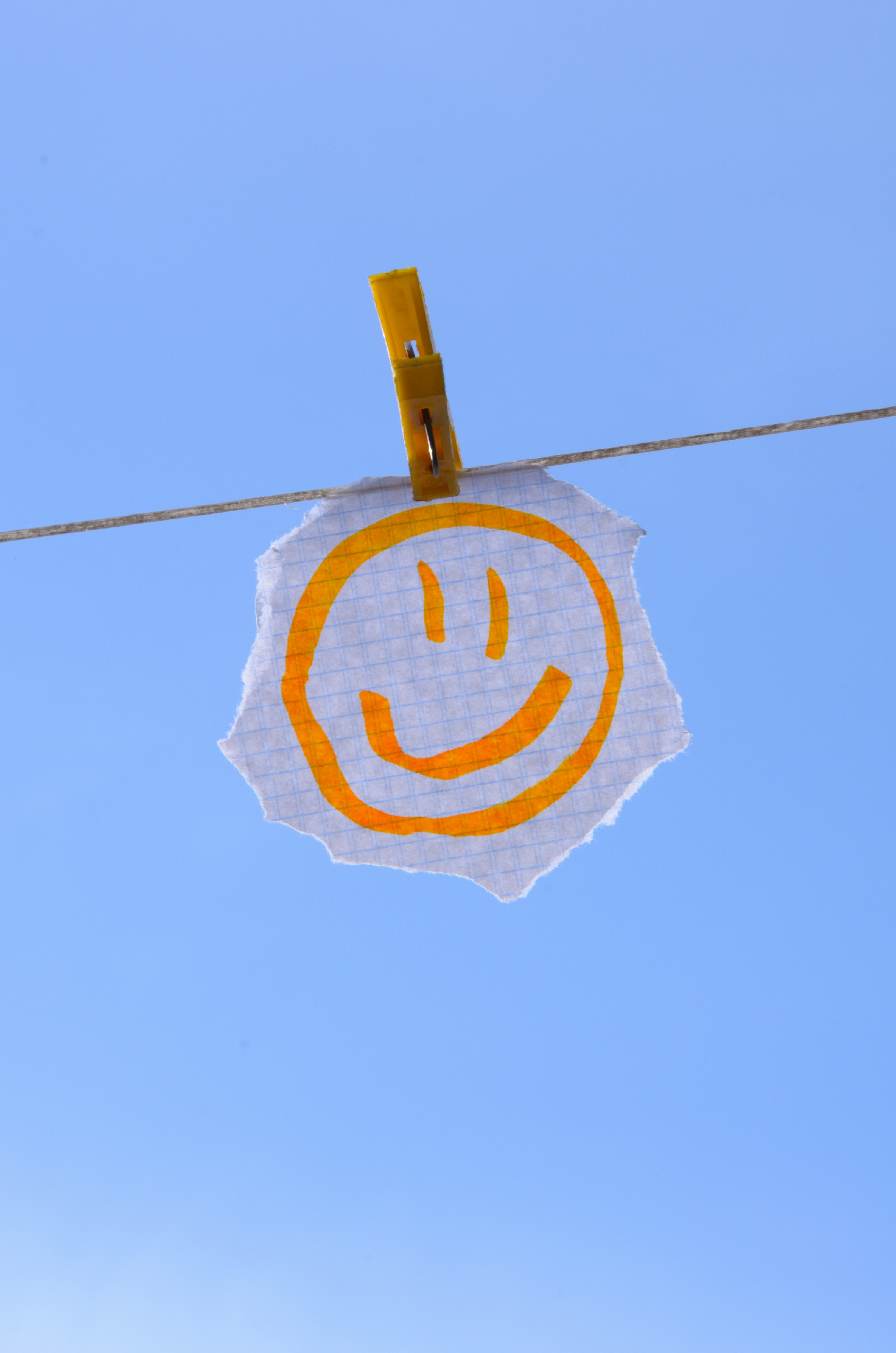 A smiley face sign hanging from a clothes line photo – Free Blue Image ...