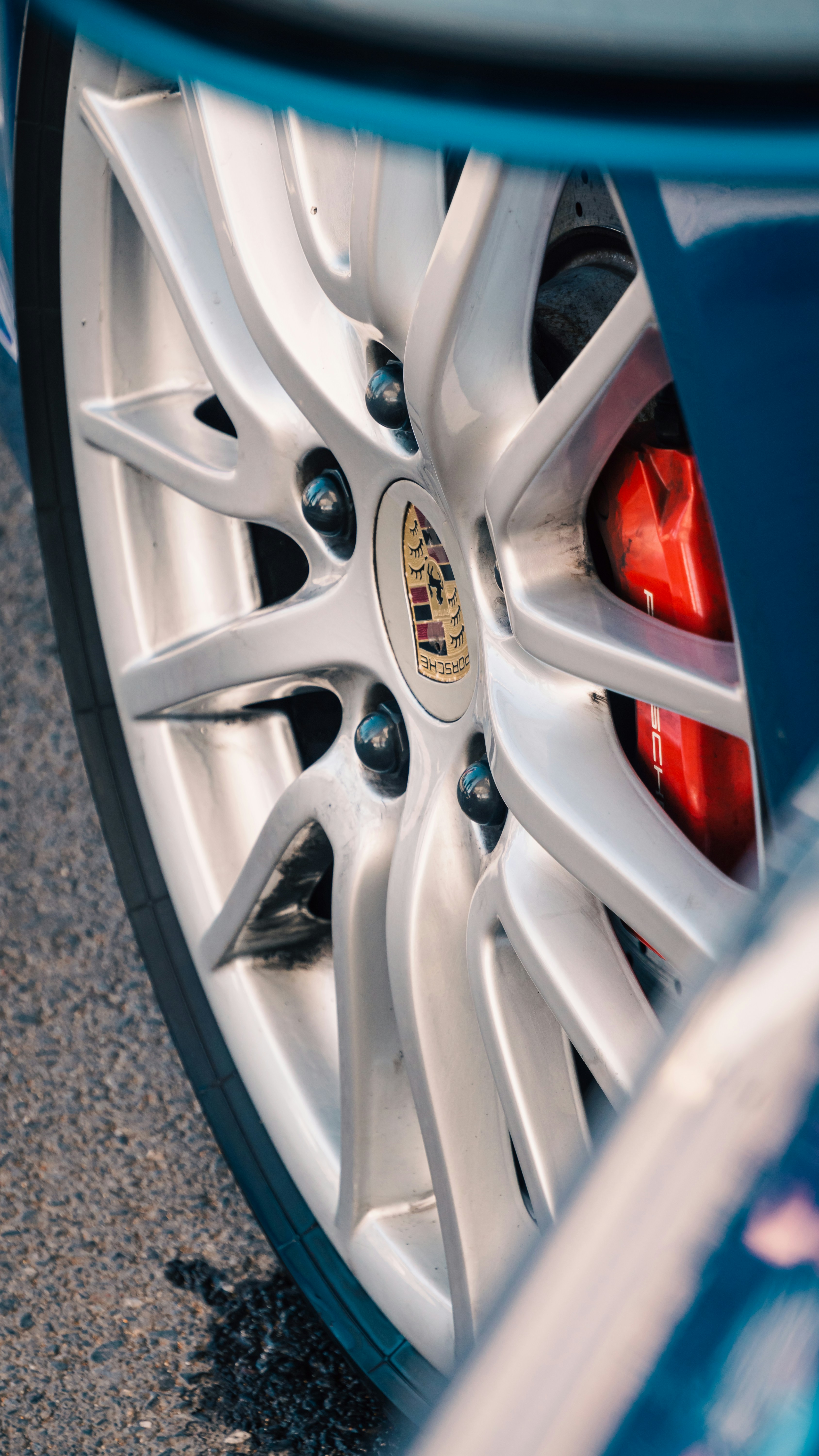 Close-Up on Precision: A Porsche Wheel Reveals Silver Spokes and a Scarlet Caliper