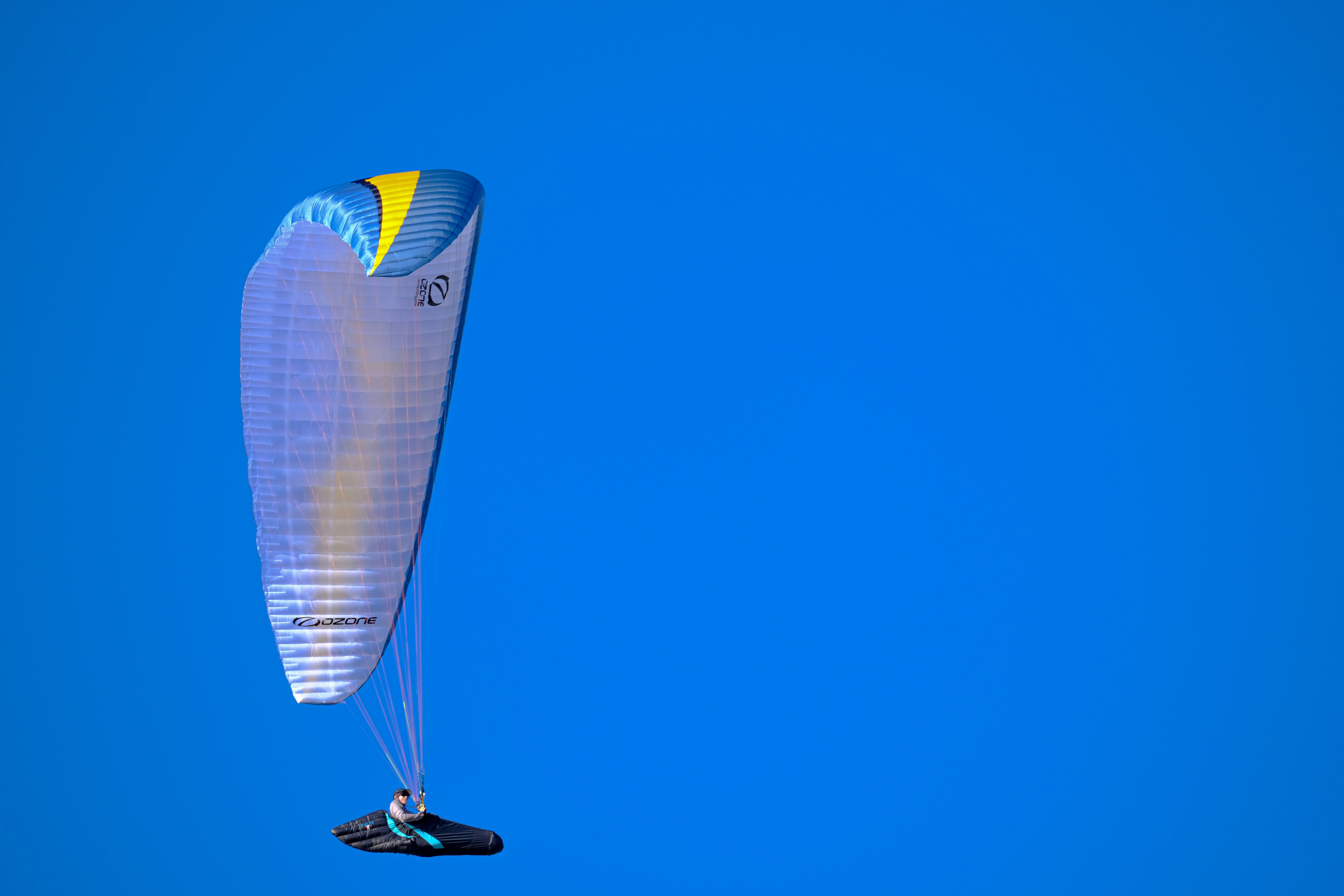 Azure Caravel Against a Velvet Blue: A Solo Paraglider Soars