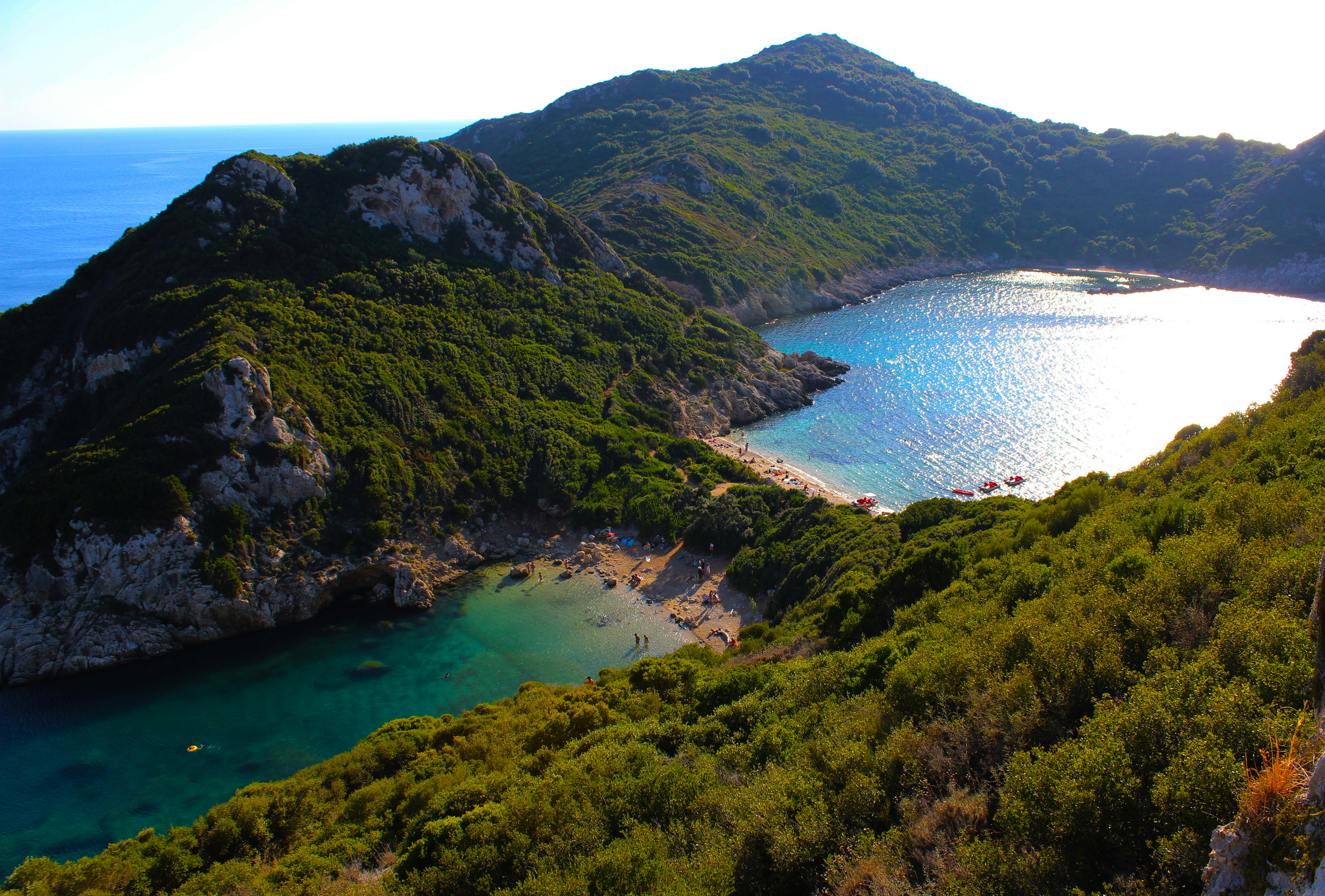 Aerial view of a secluded beach nestled between lush green hills and tranquil blue waters. The scene captures the harmony of nature and invites exploration.