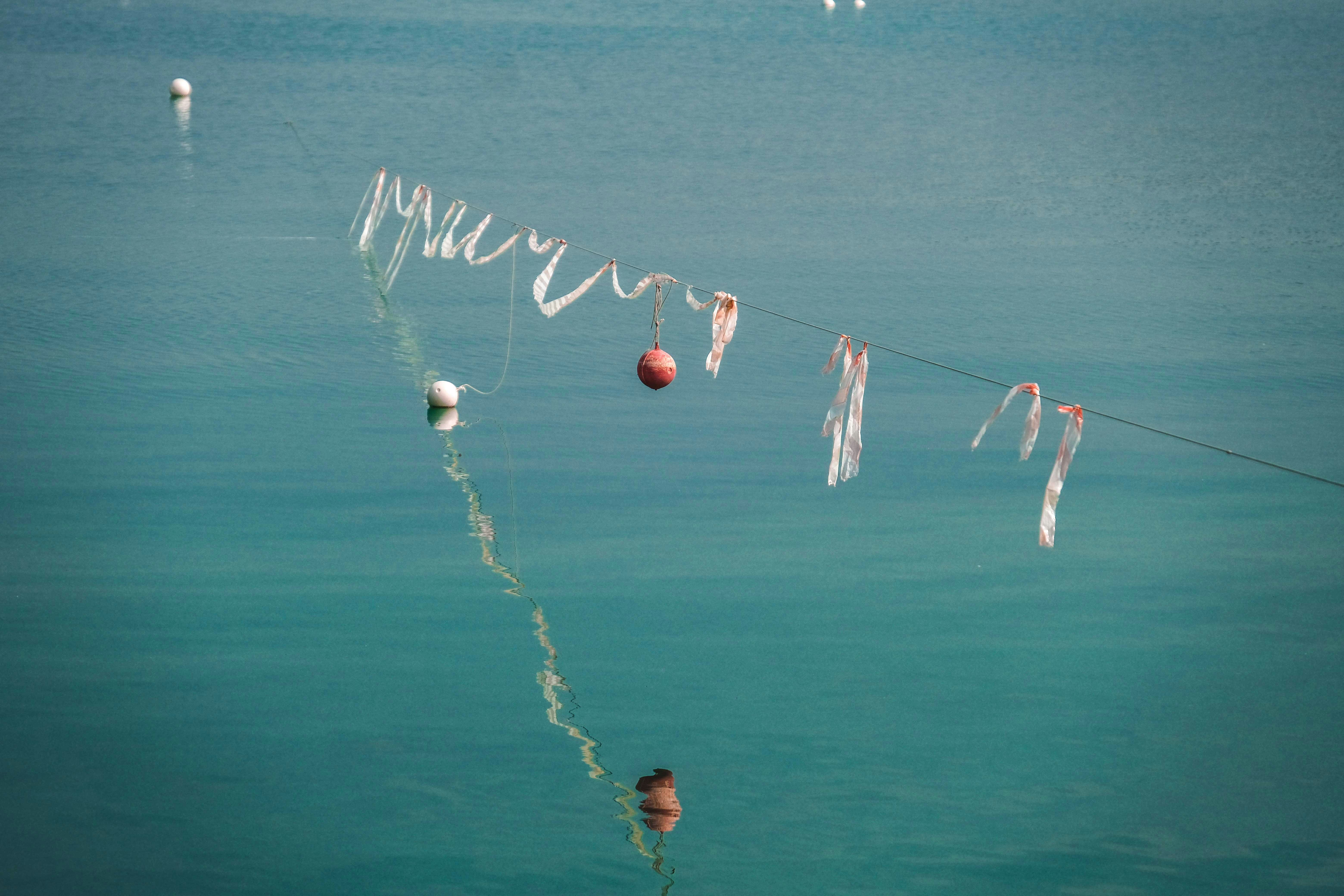 A string of balls floating on top of a body of water photo – Free Sea ...