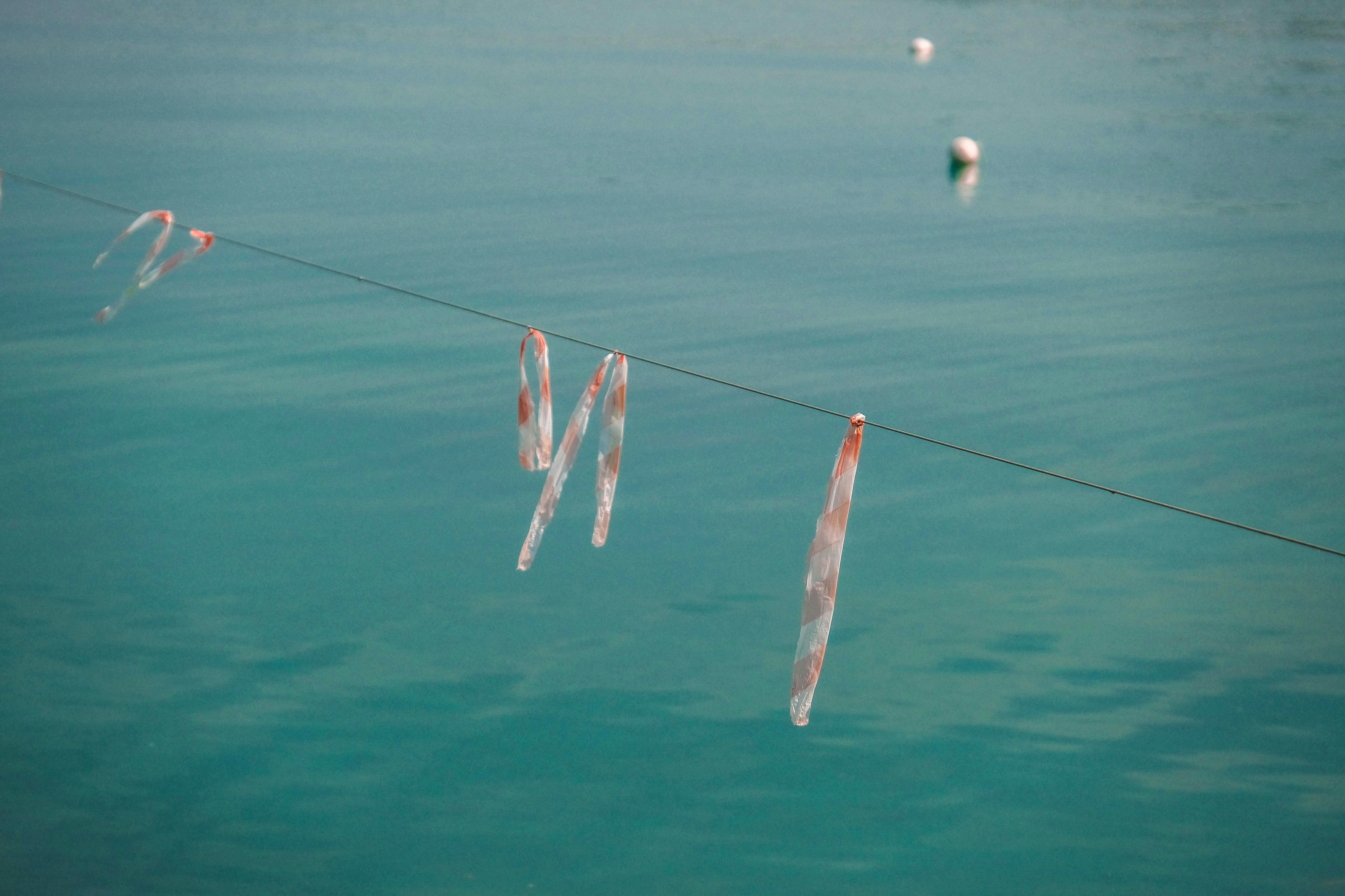 Teal Silence: Translucent Clothespins on a Wire Above Calm Water