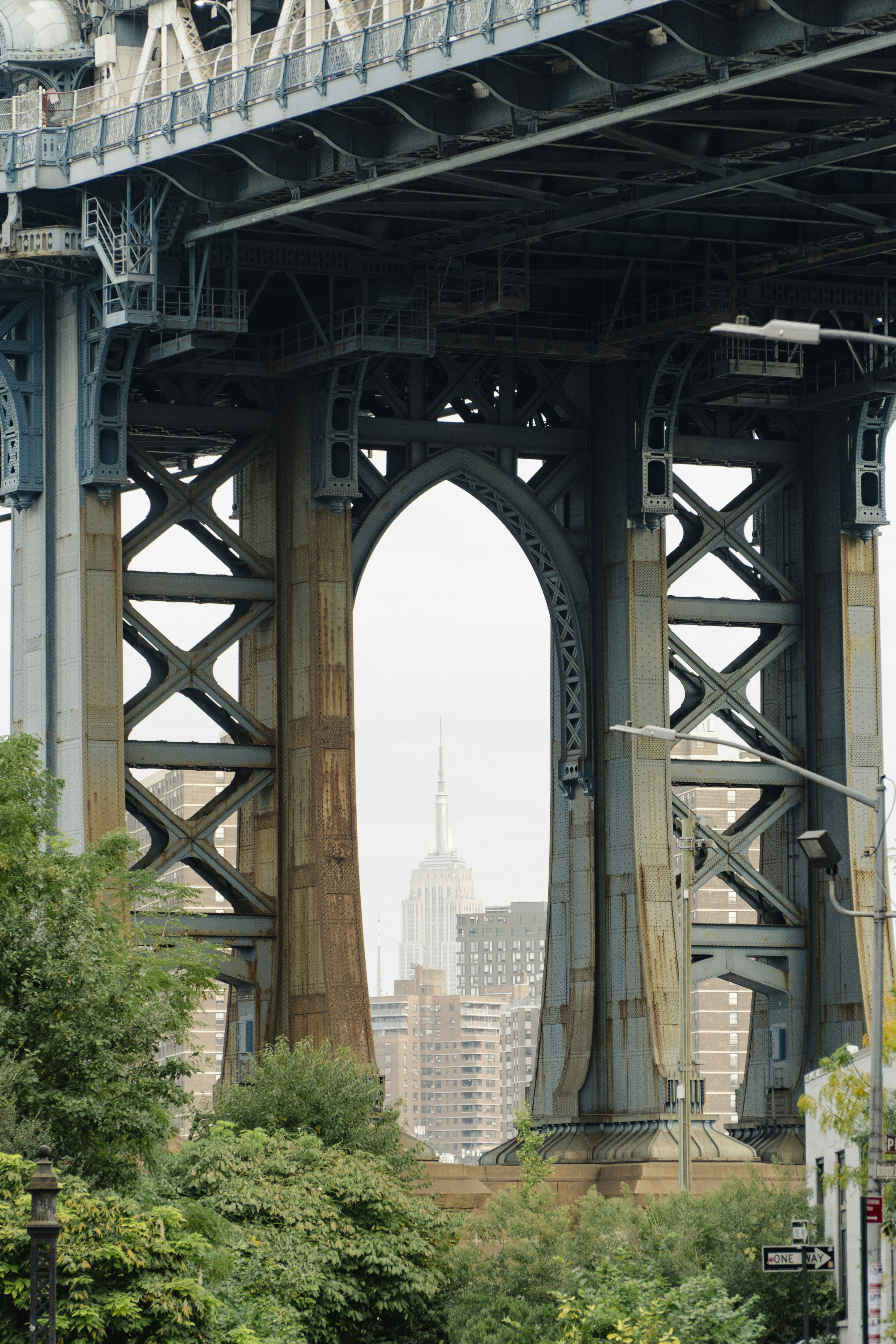 Archway View: Empire State Building framed by a weathered steel bridge