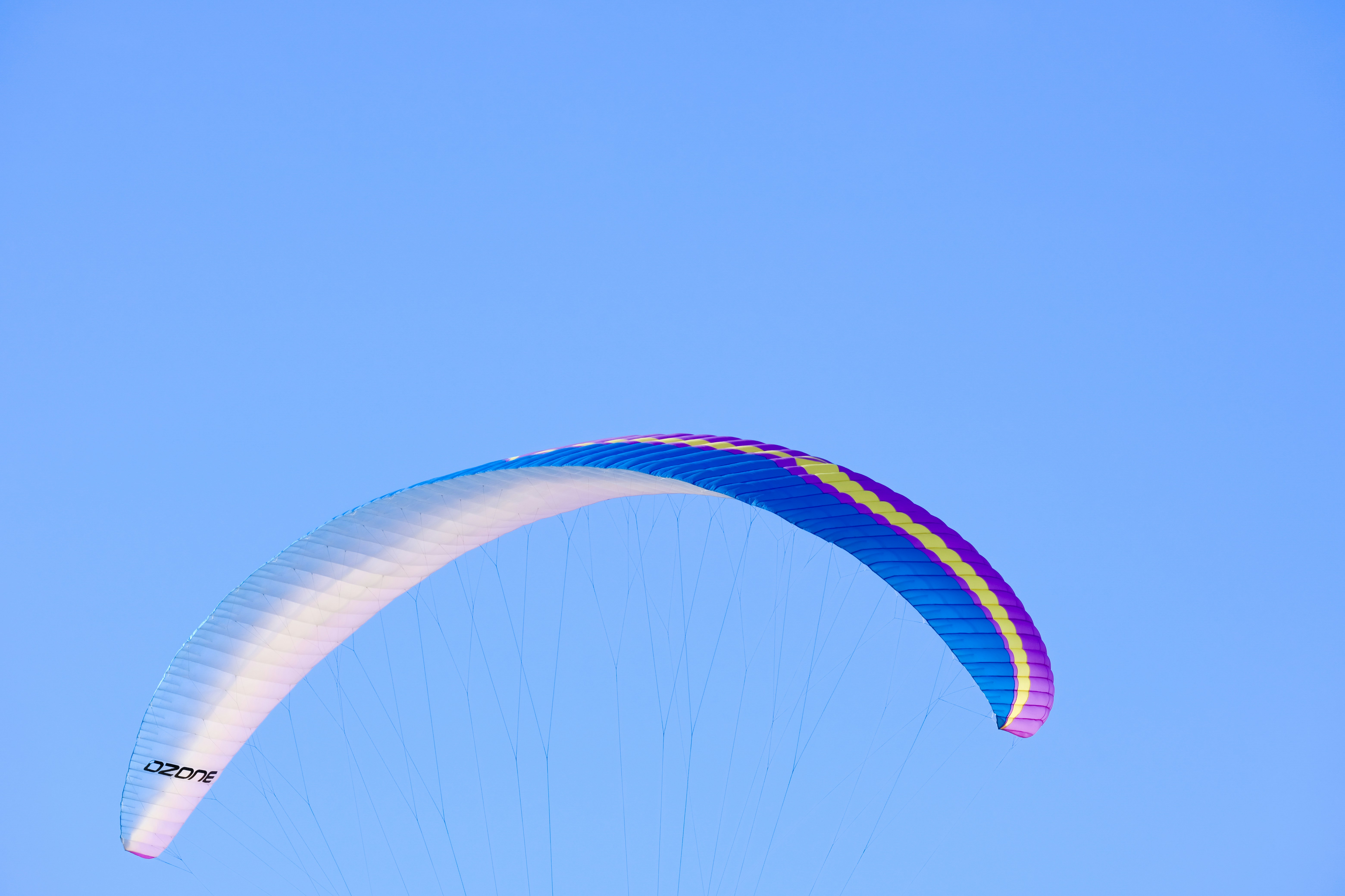 Winged Arc Over a Cobalt Sky: A Paraglider in Quiet Ascent