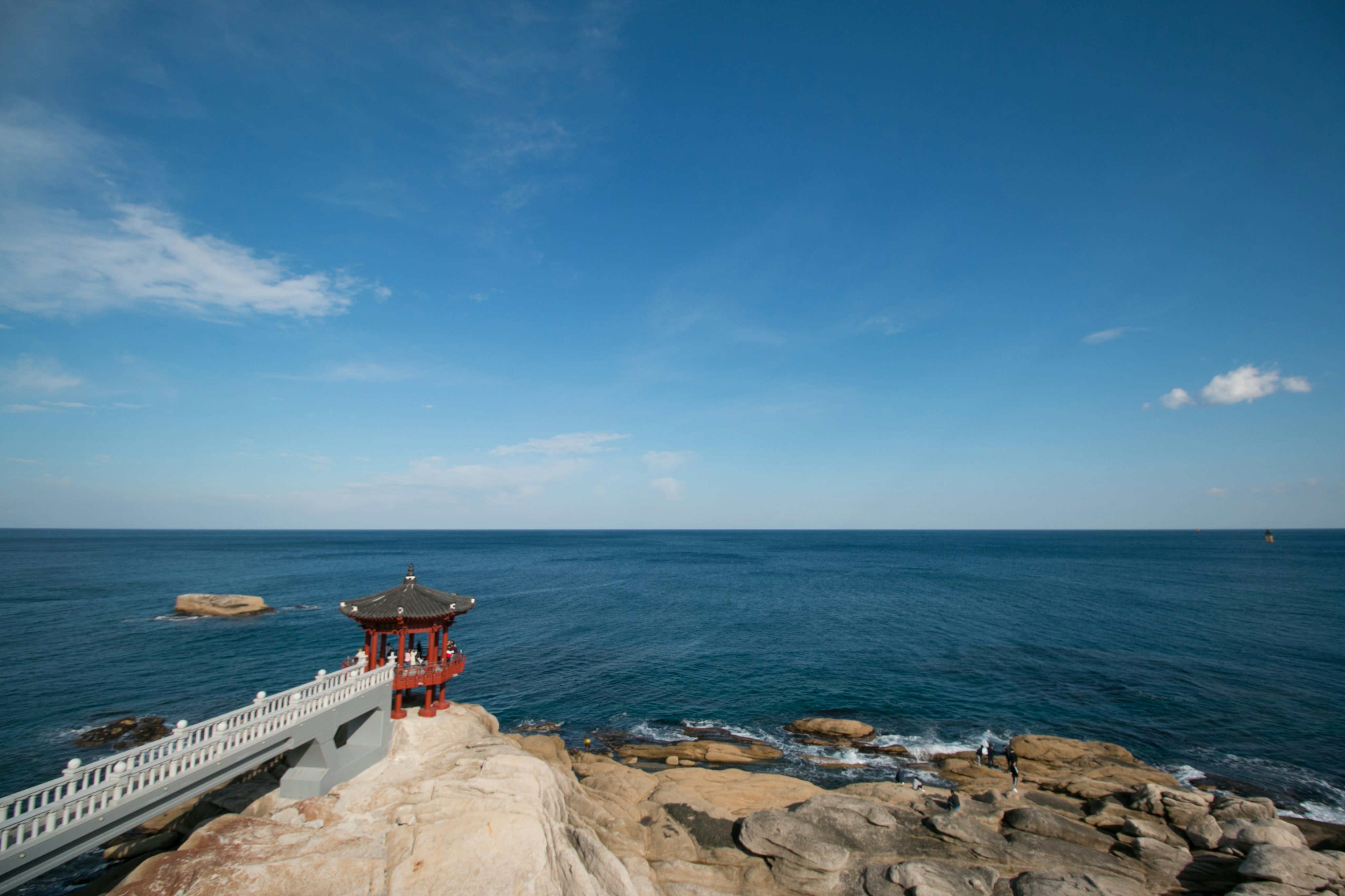 A red and white pagoda sitting on top of a cliff next to the ocean ...